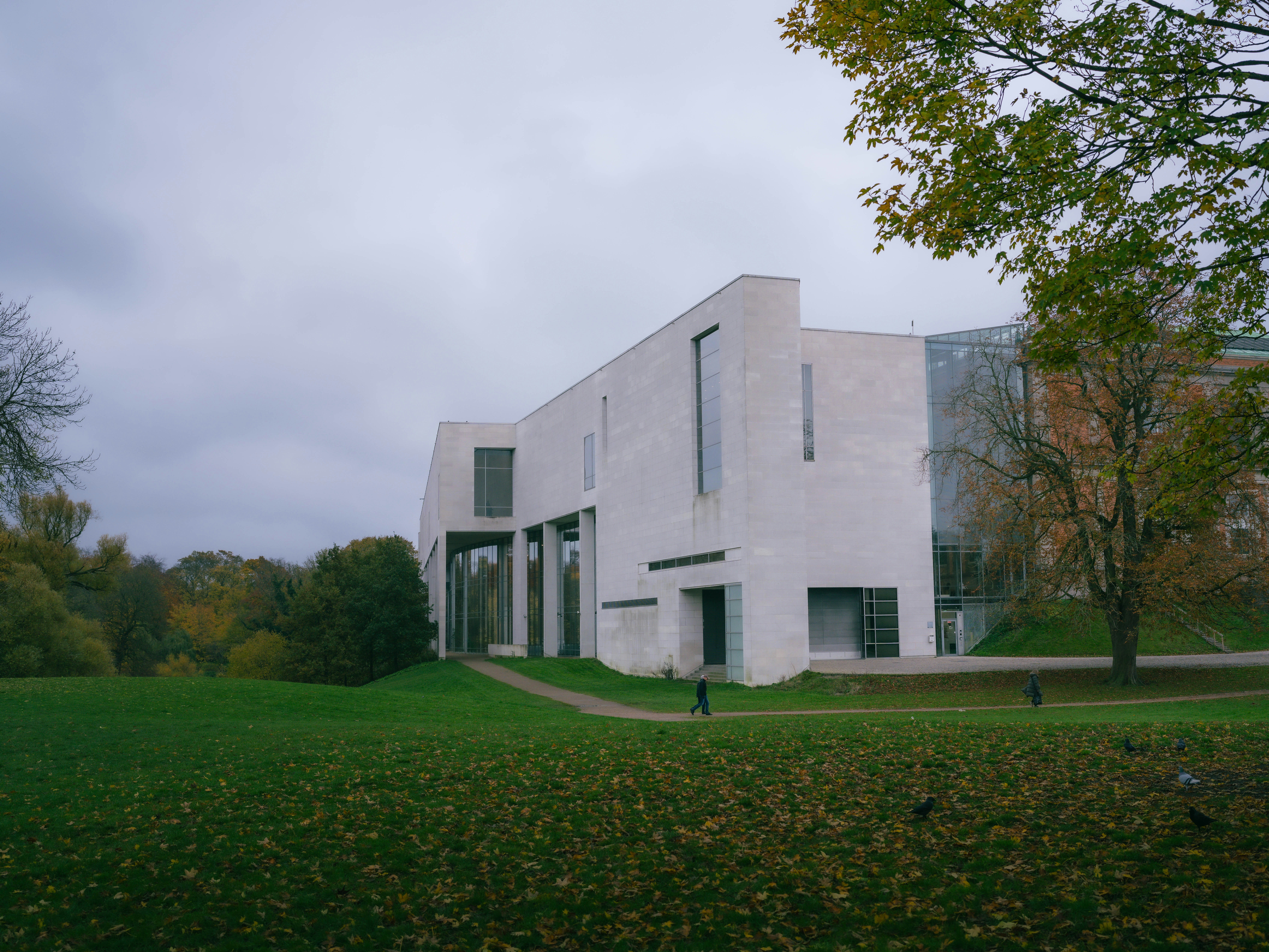 A contemporary building seamlessly integrated into a lush green landscape, surrounded by autumn foliage.