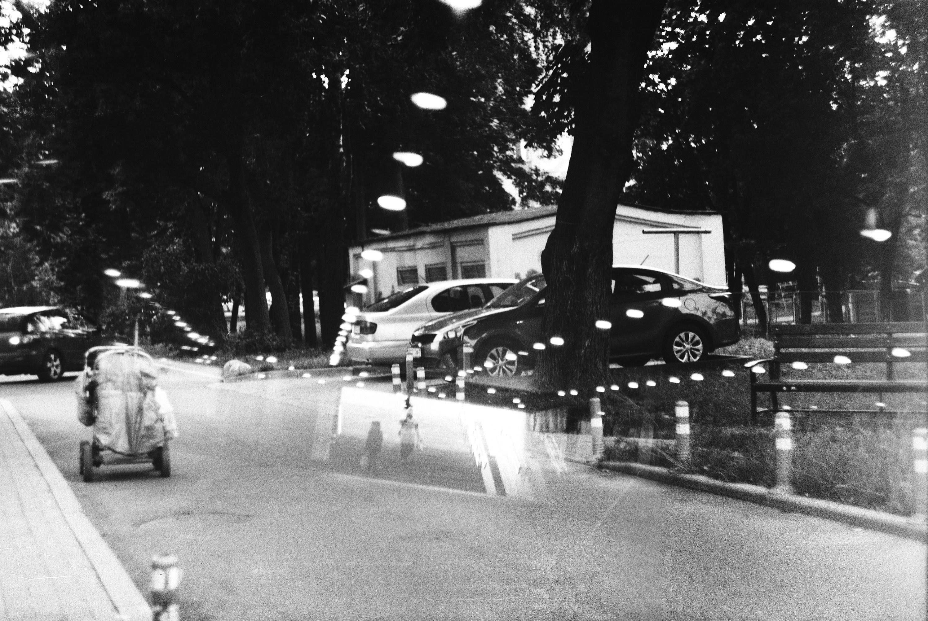 A moped drives past parked cars on a street.