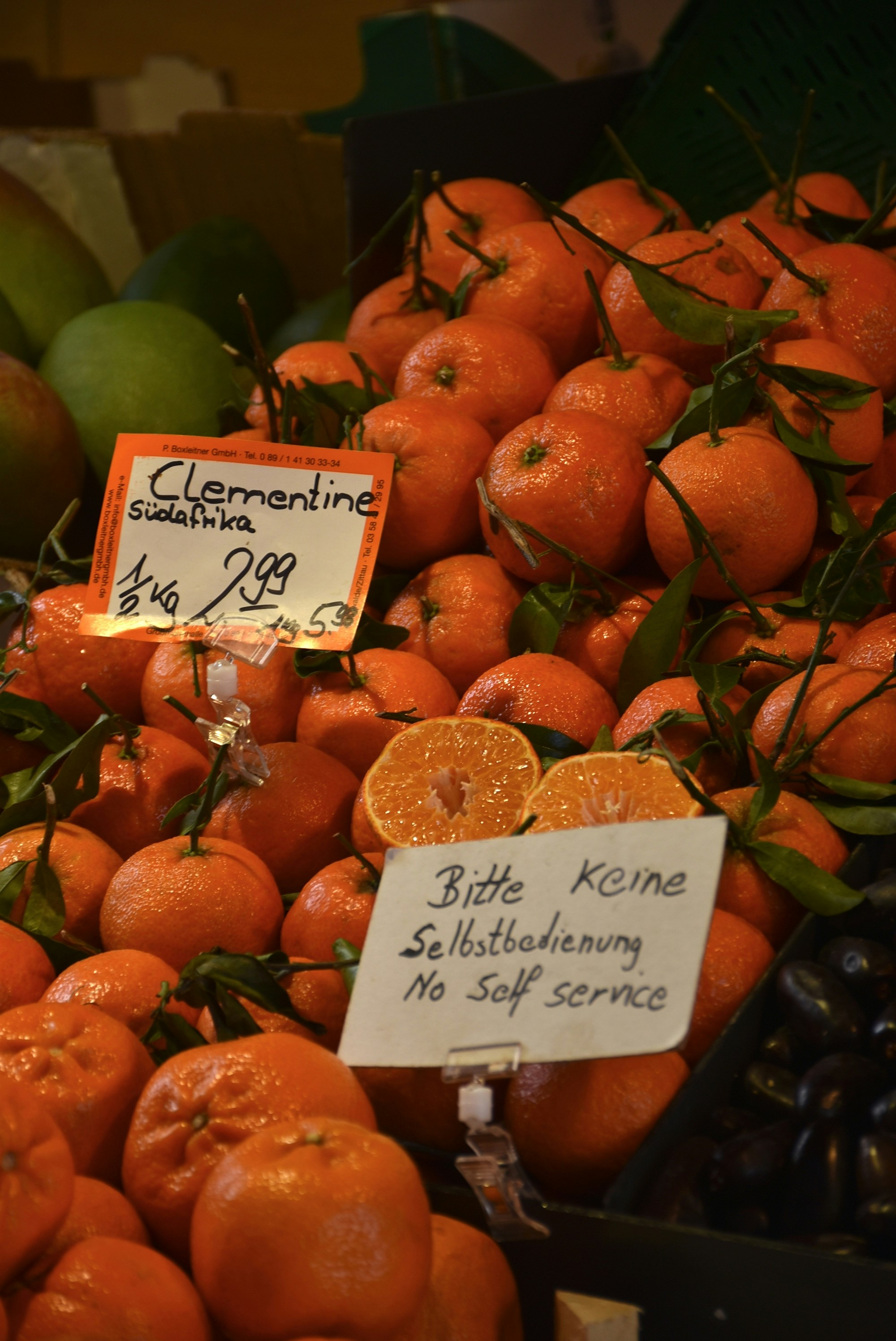 Vibrant clementines stacked in a market, accompanied by price tags in German. The scene captures the essence of fresh produce shopping.
