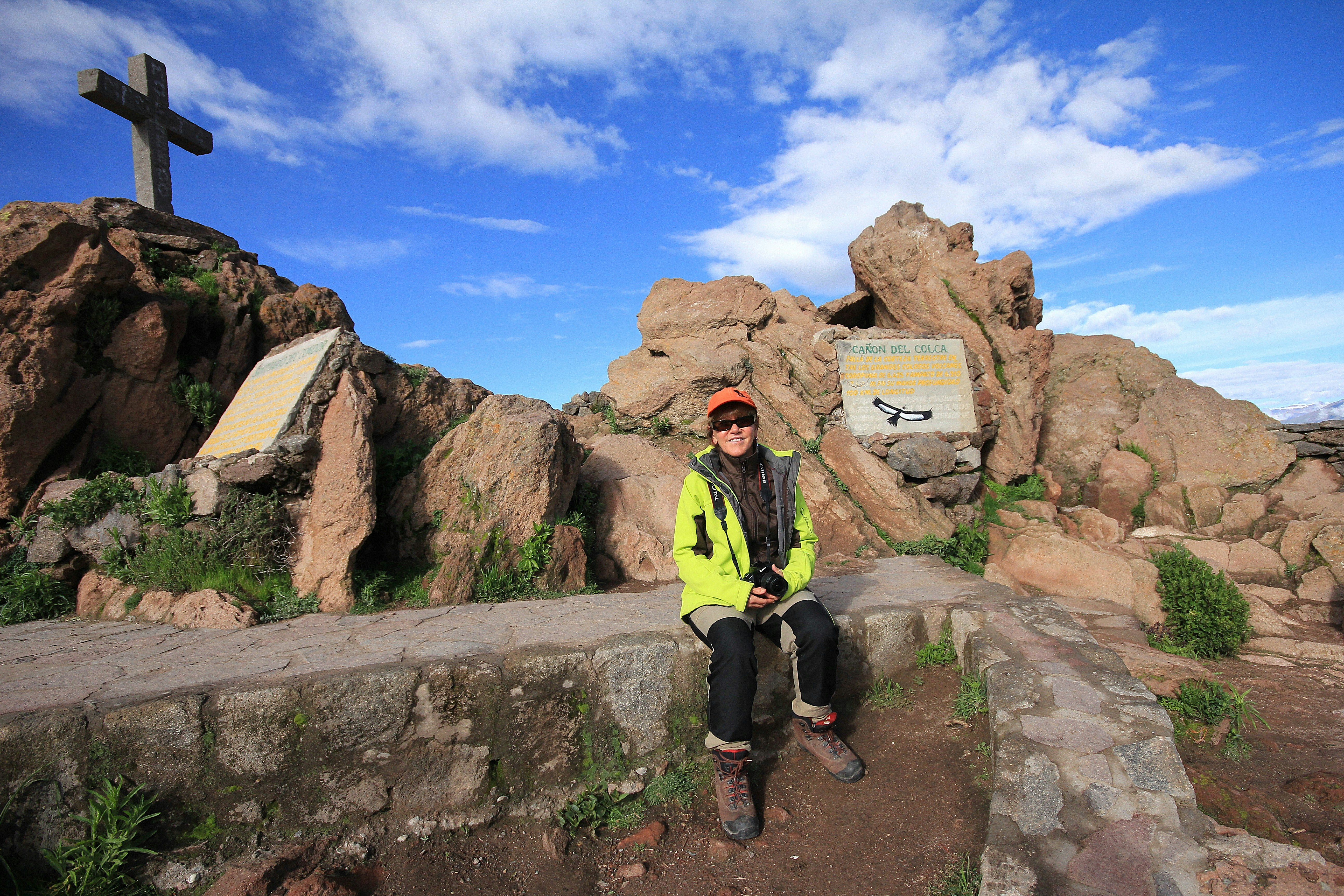 Neon-Clad Explorer at a Wind-Worn Summit Cross