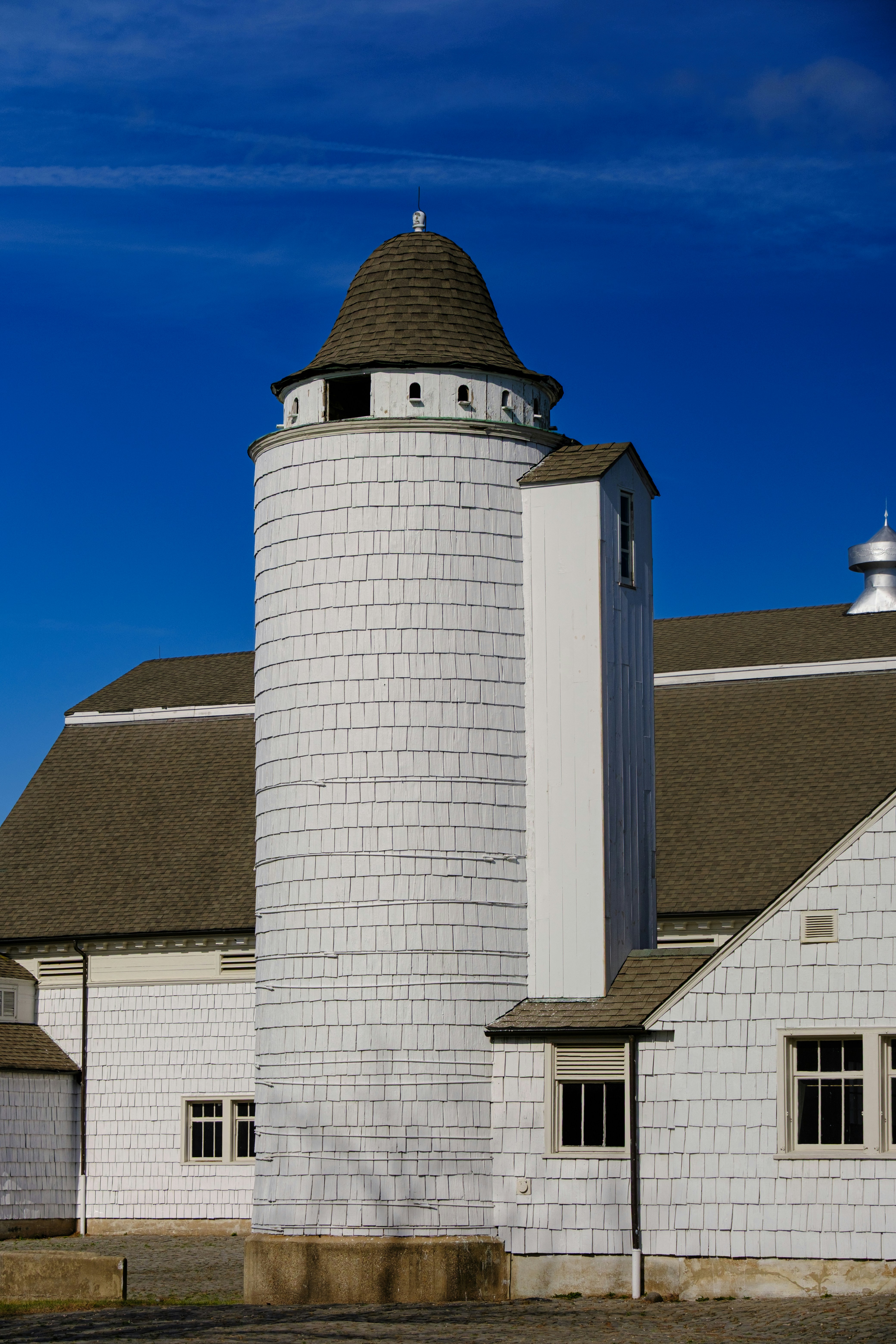 The Tall White Silo: Farm Architecture Framed by a Deep Blue Sky