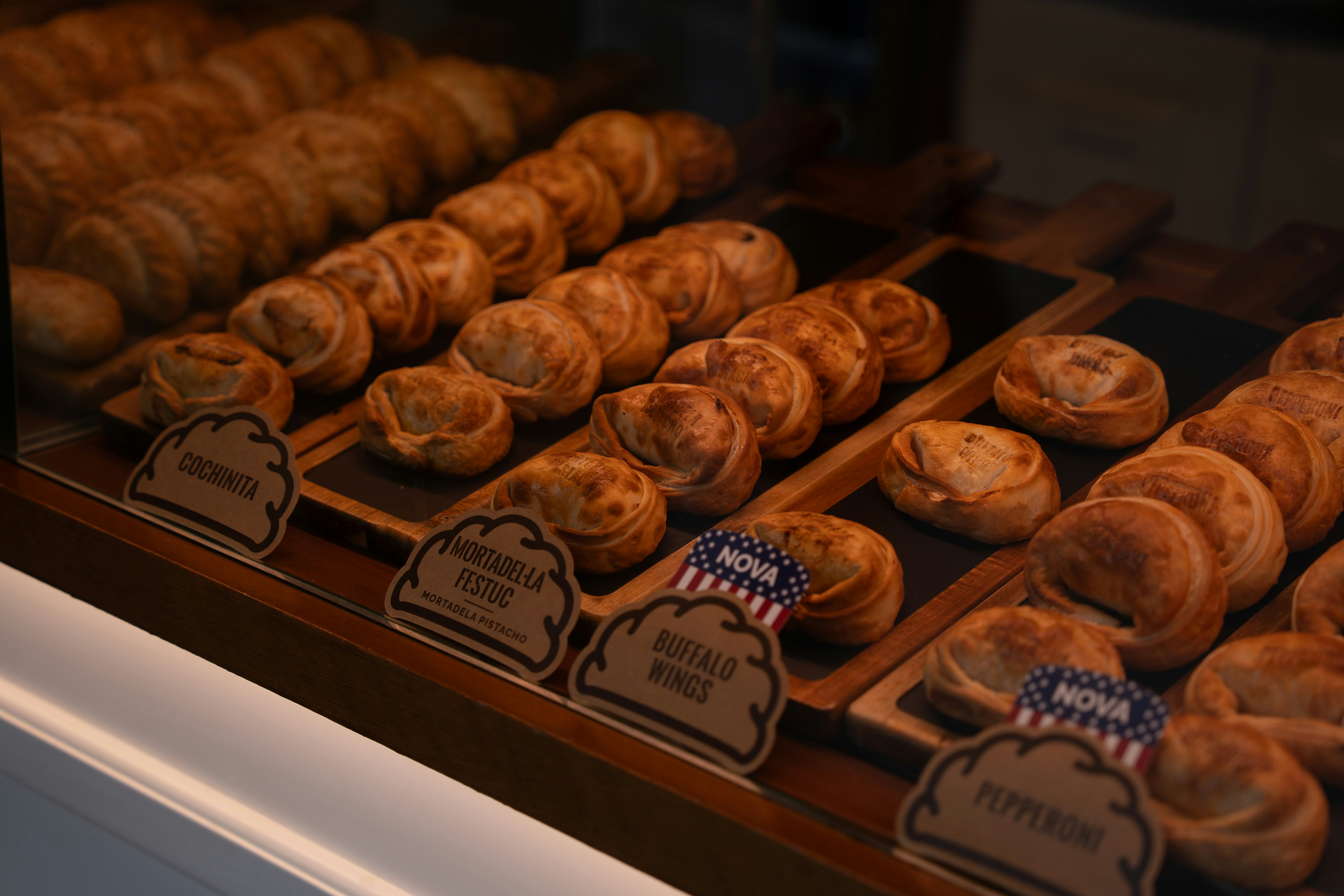 An enticing display of various savory pastries, each labeled with unique flavors, showcased in a glass case.