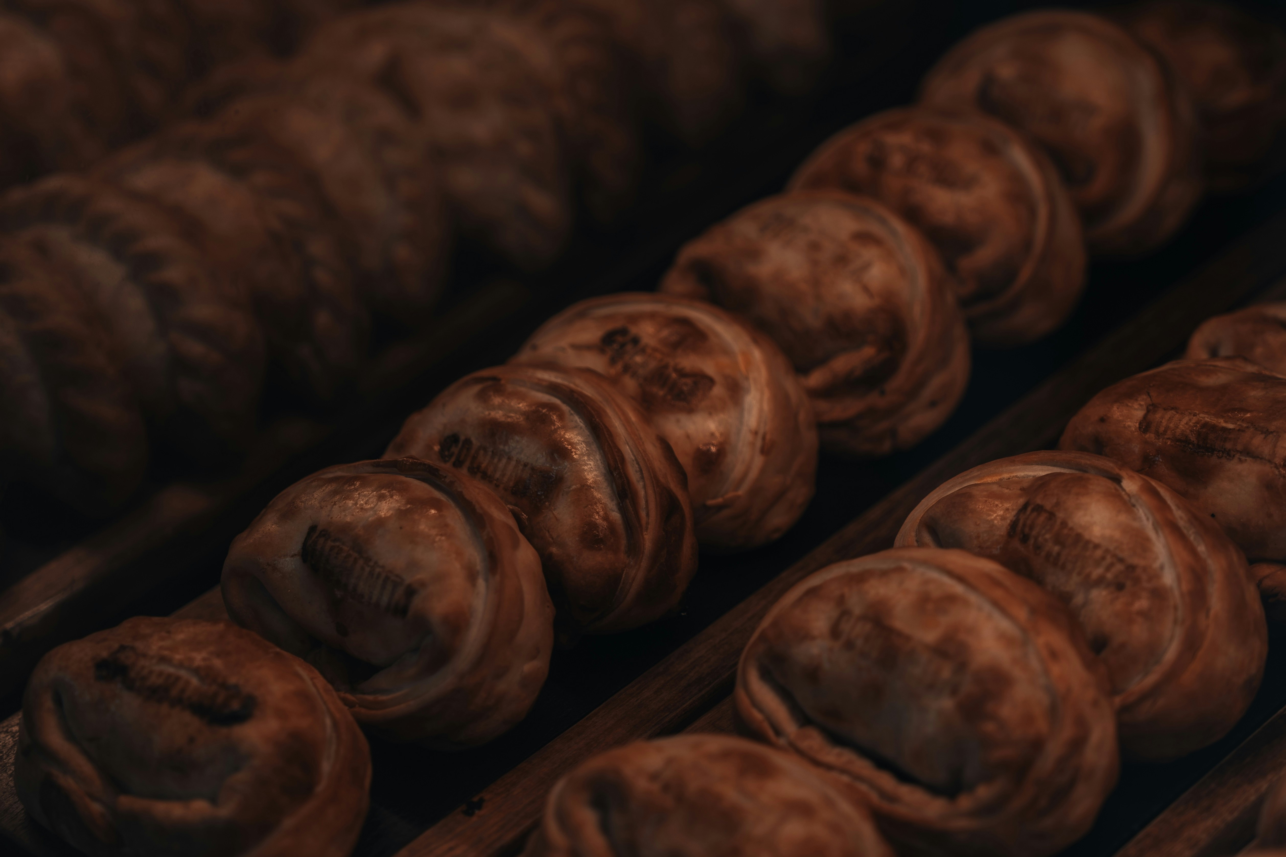 Ember-Lit Croissant Row: Quiet Heat on a Dim Bakery Shelf