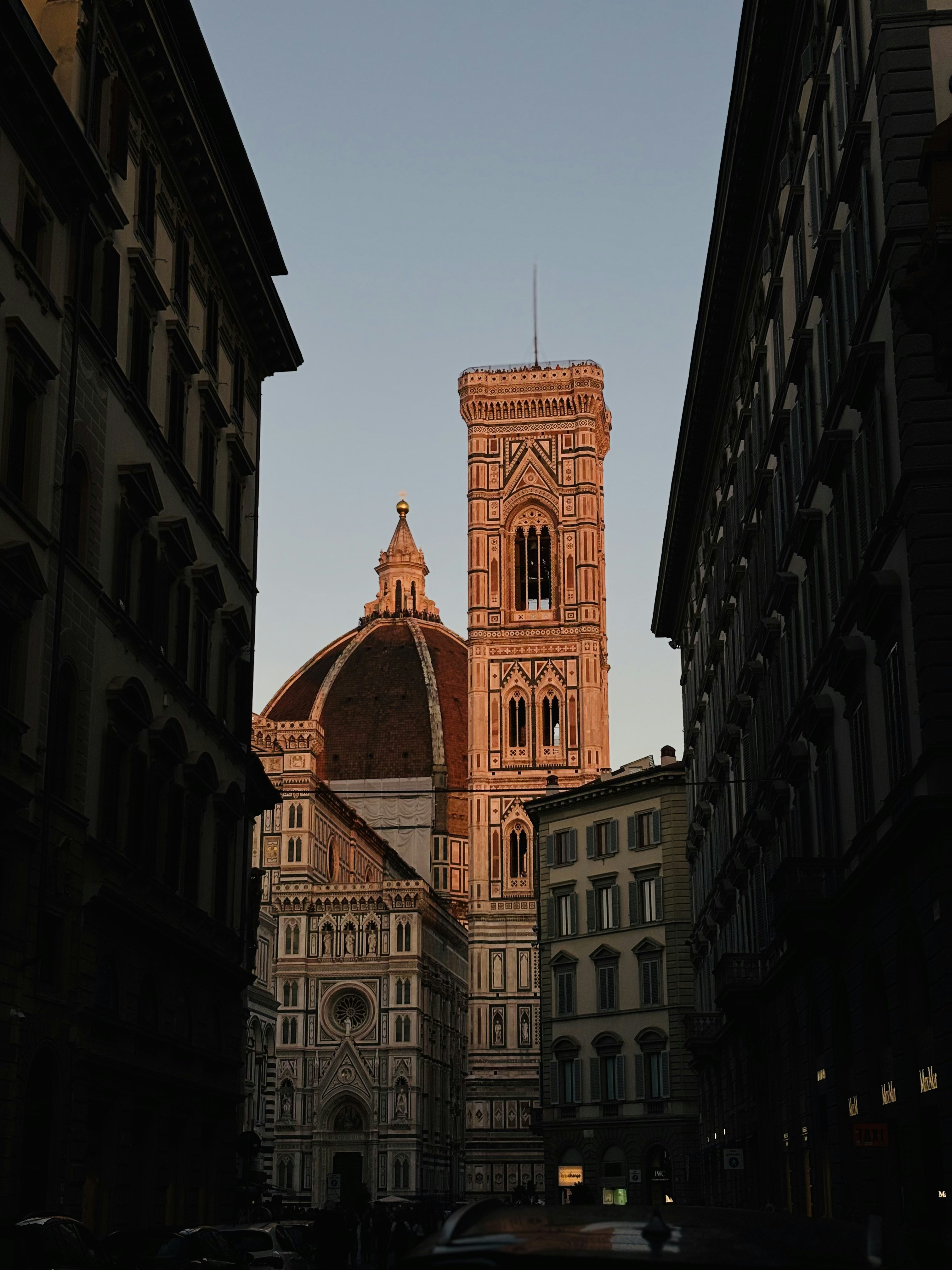 Florence's iconic Duomo and Giotto's Campanile framed by narrow streets at dusk, showcasing intricate architectural details. 