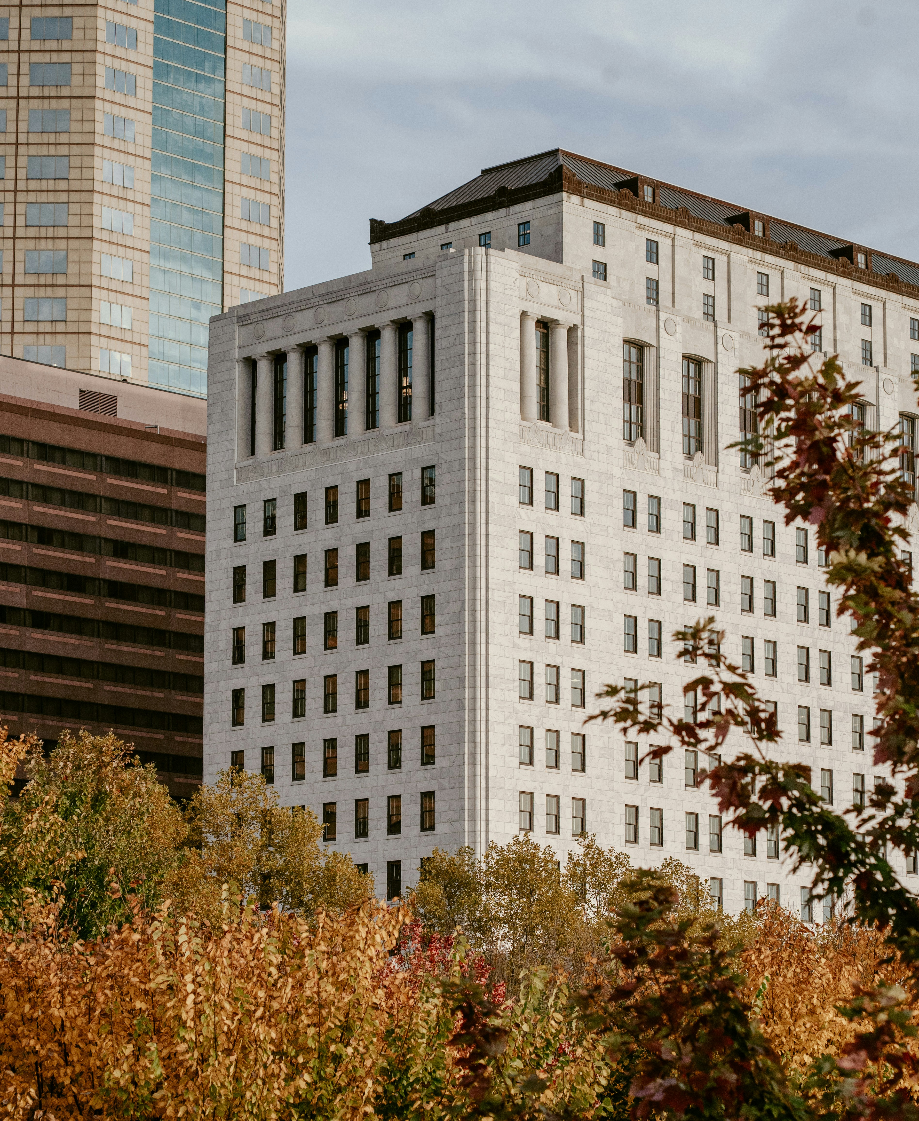 Historic building juxtaposed against modern skyscrapers, framed by colorful autumn foliage.