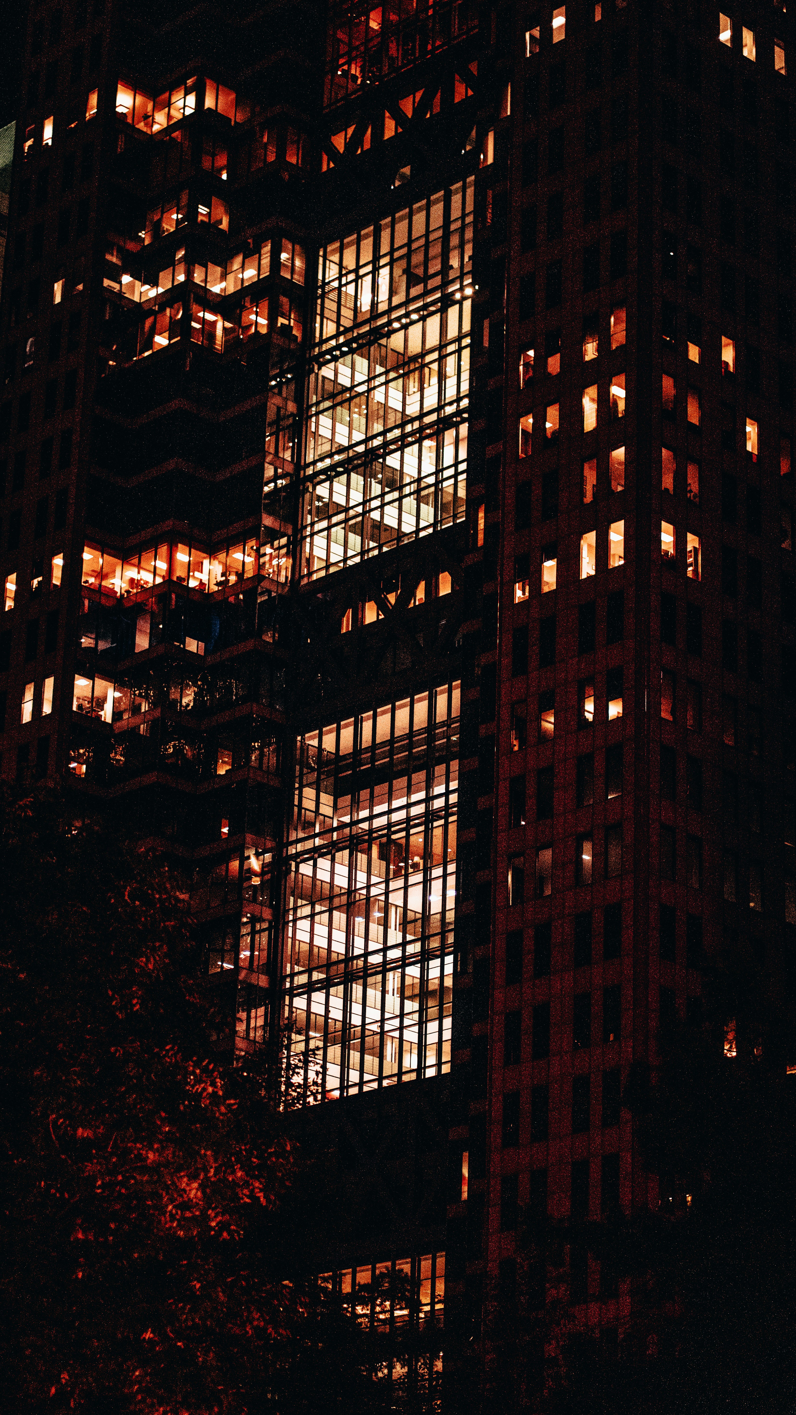 Illuminated office spaces within a modern skyscraper at night, showcasing the interplay of light and architecture.