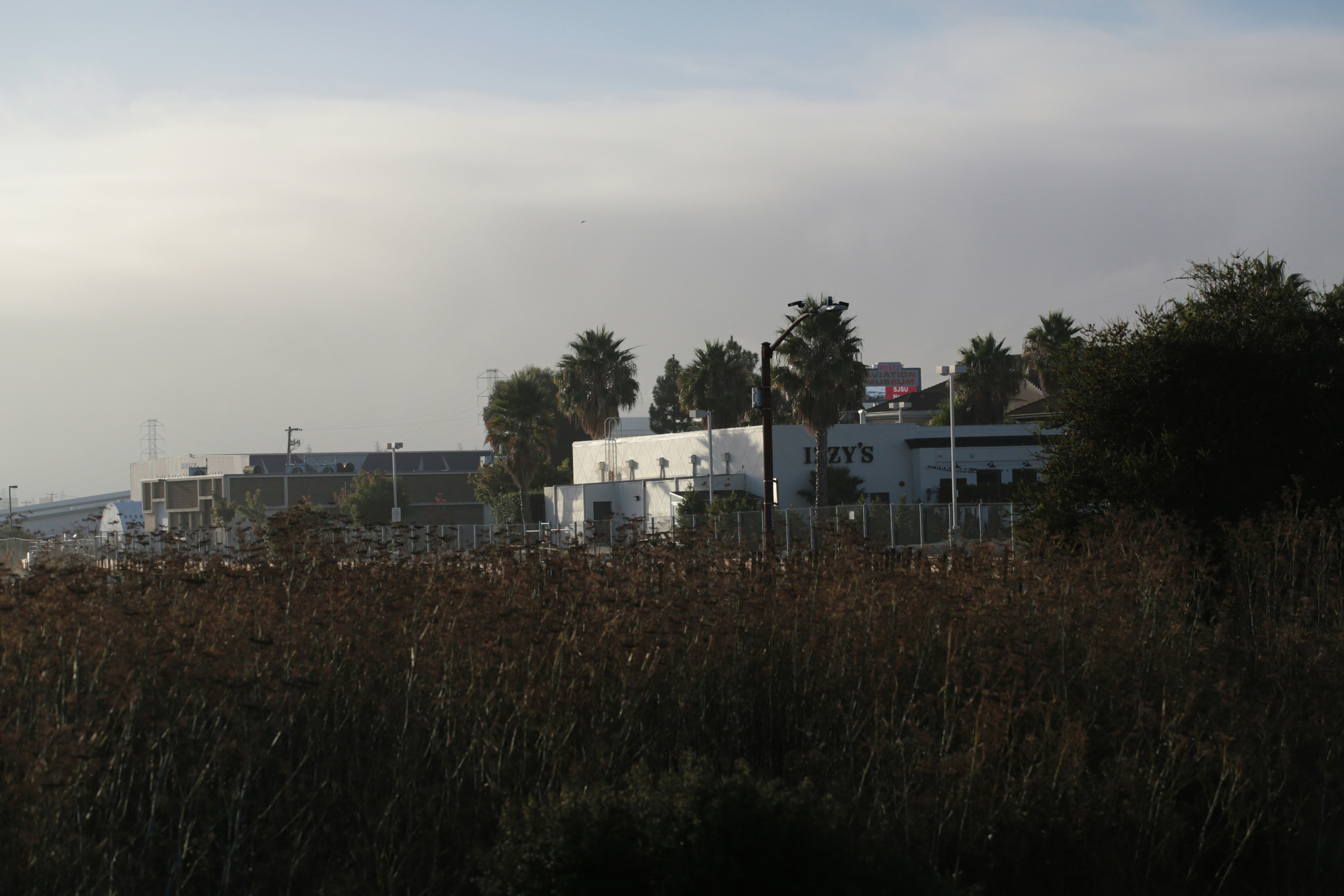 Industrial buildings and trees under a hazy sky.