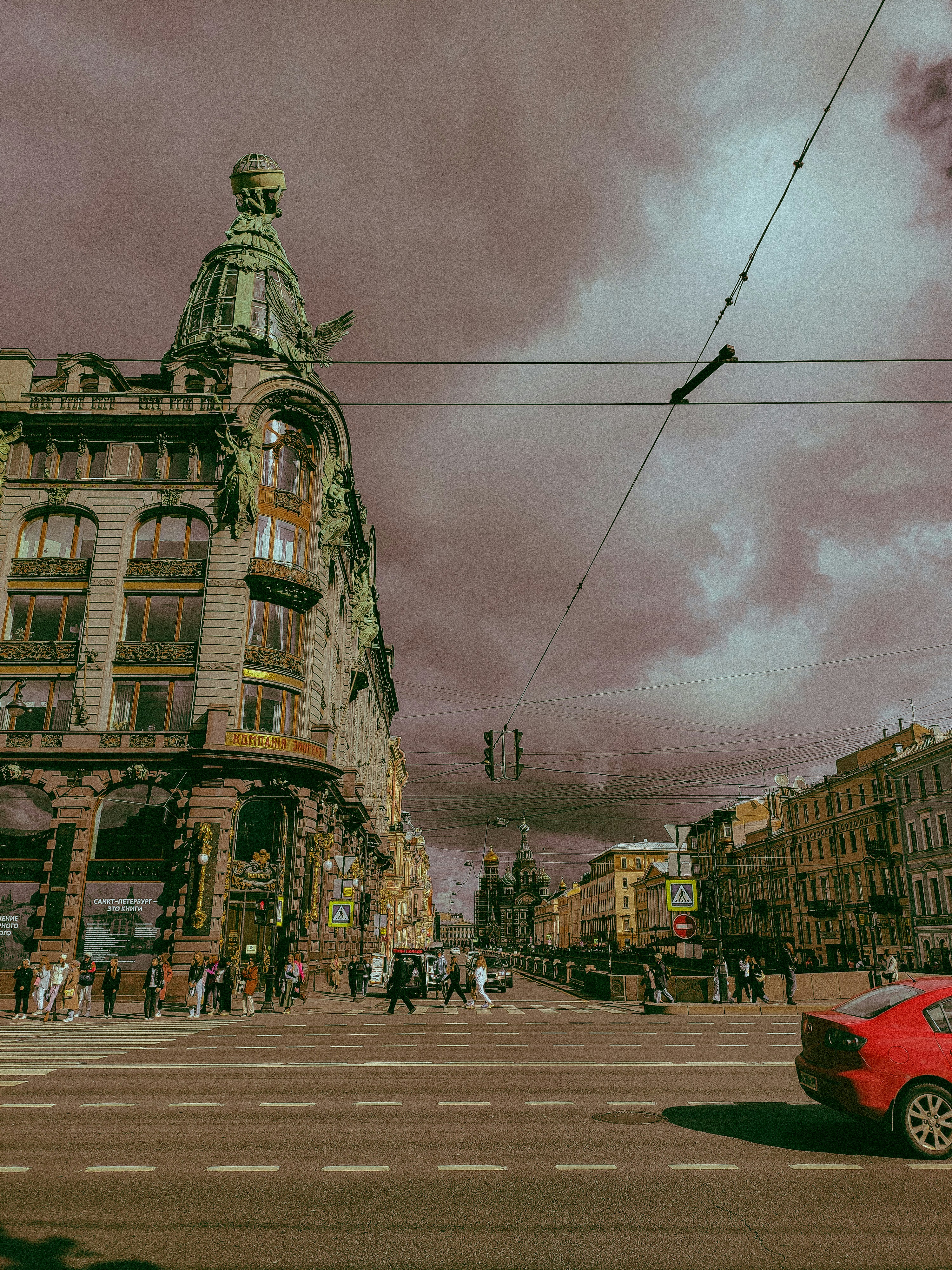 Historic building with intricate architecture under a dramatic sky, bustling pedestrians crossing the street below.