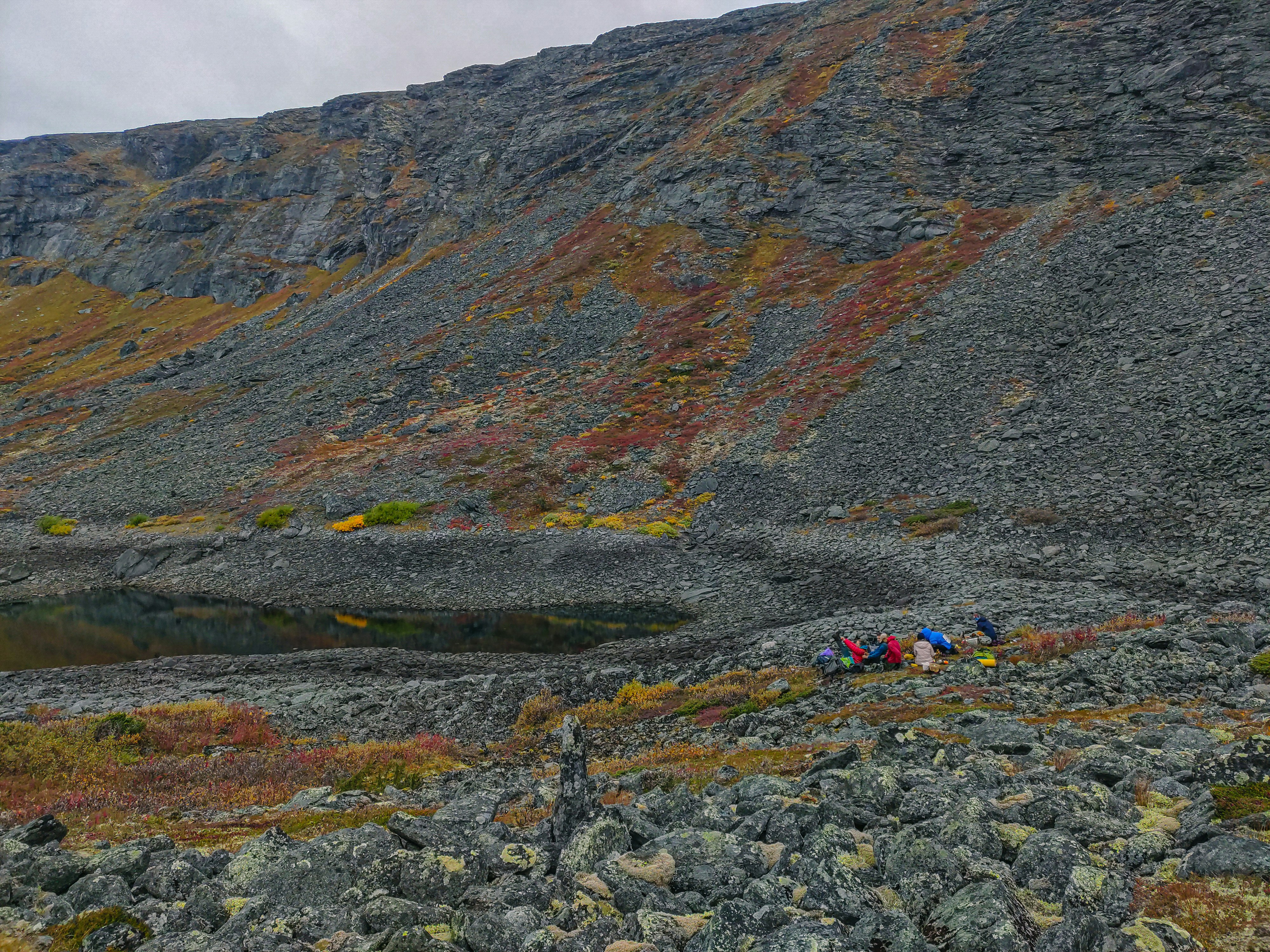 Colorful Trek Across a Rugged Alpine Scree by a Quiet Tarn