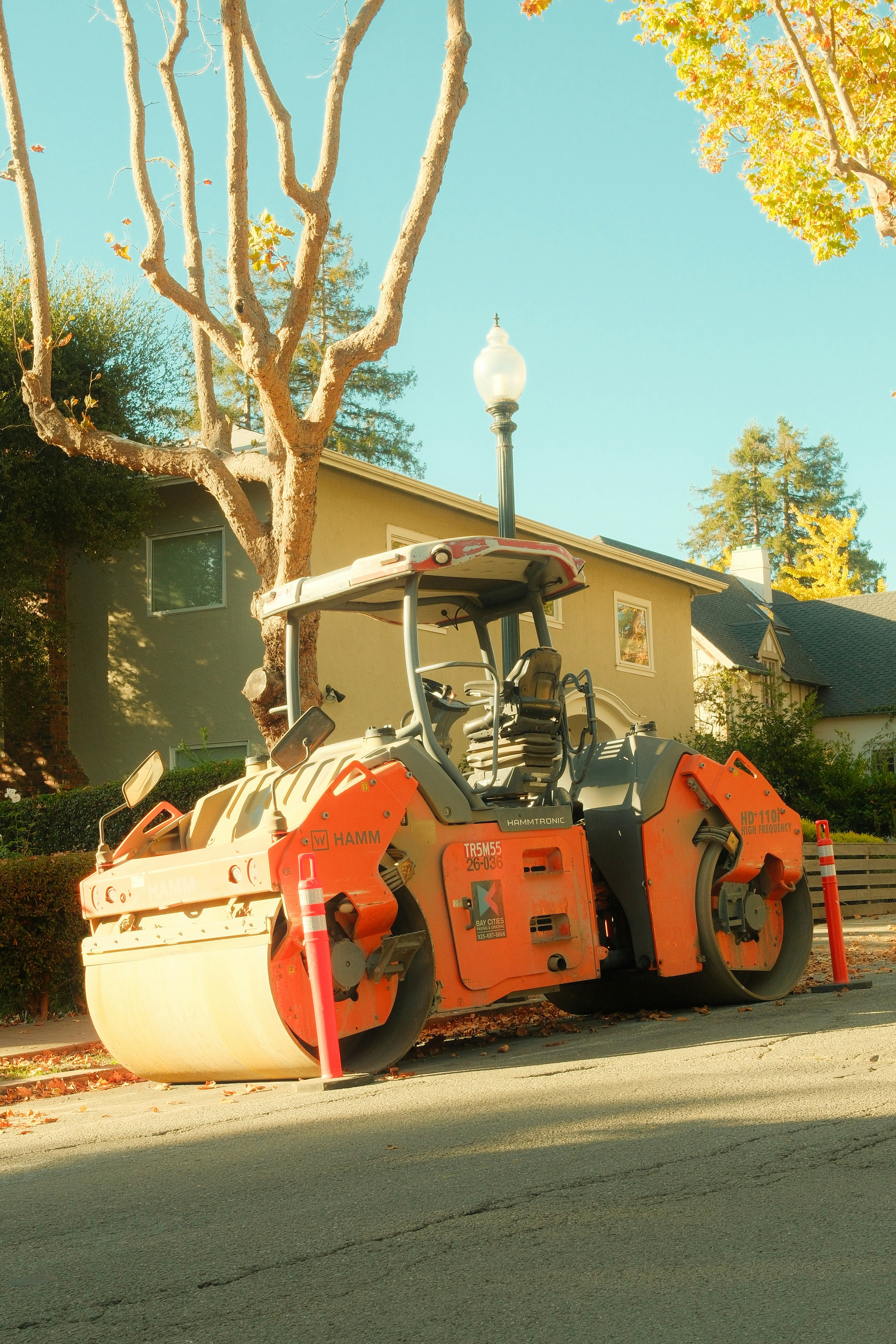 An orange steamroller parked on a street.
