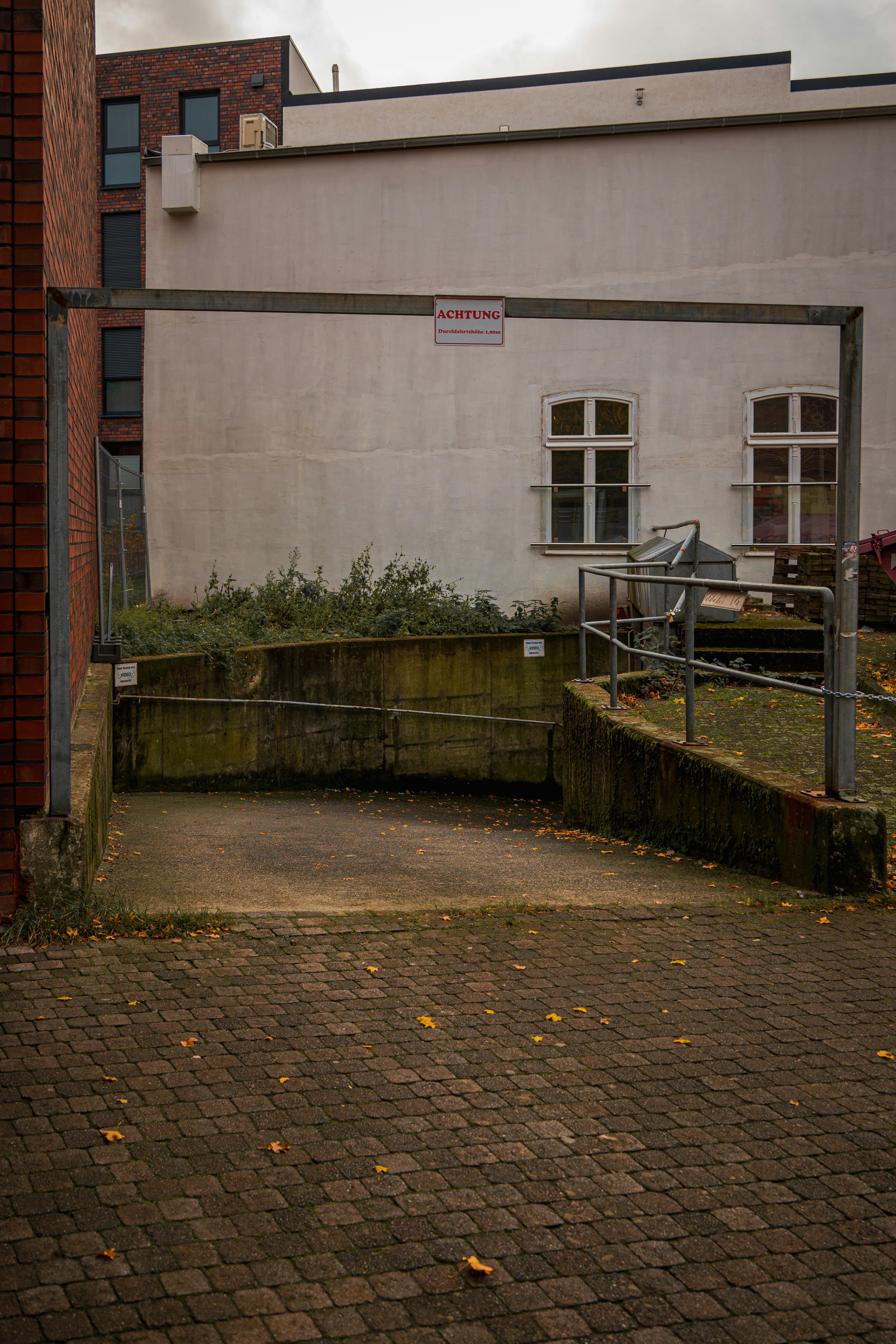 Achtung on the Wall: A Quiet Urban Ramp Beneath a White Facade