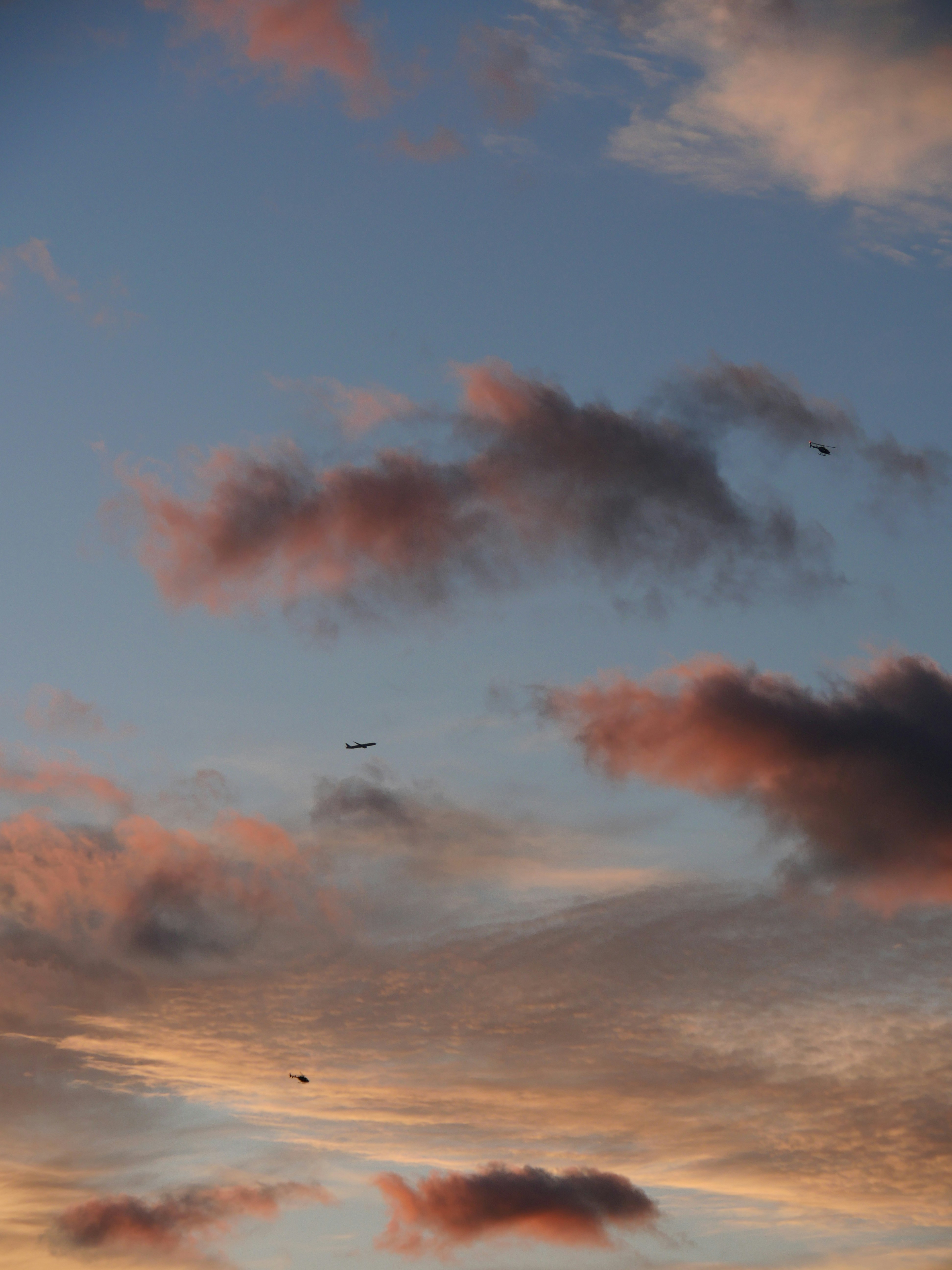 Two aircraft navigating through a vibrant sky filled with wispy clouds at dusk.