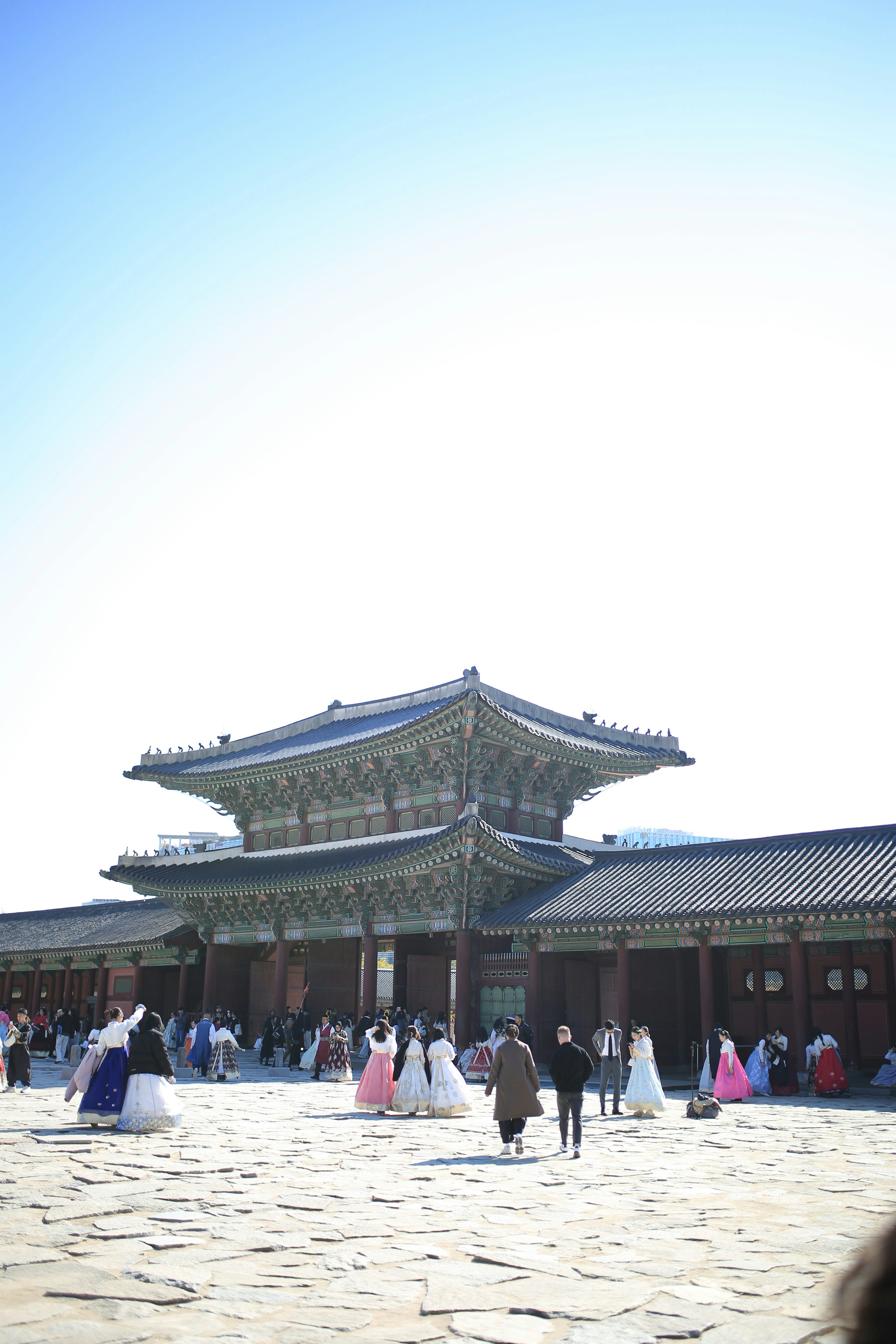 Visitors in traditional hanbok attire stroll through the historic Gyeongbokgung Palace, showcasing the blend of cultural heritage and contemporary life.