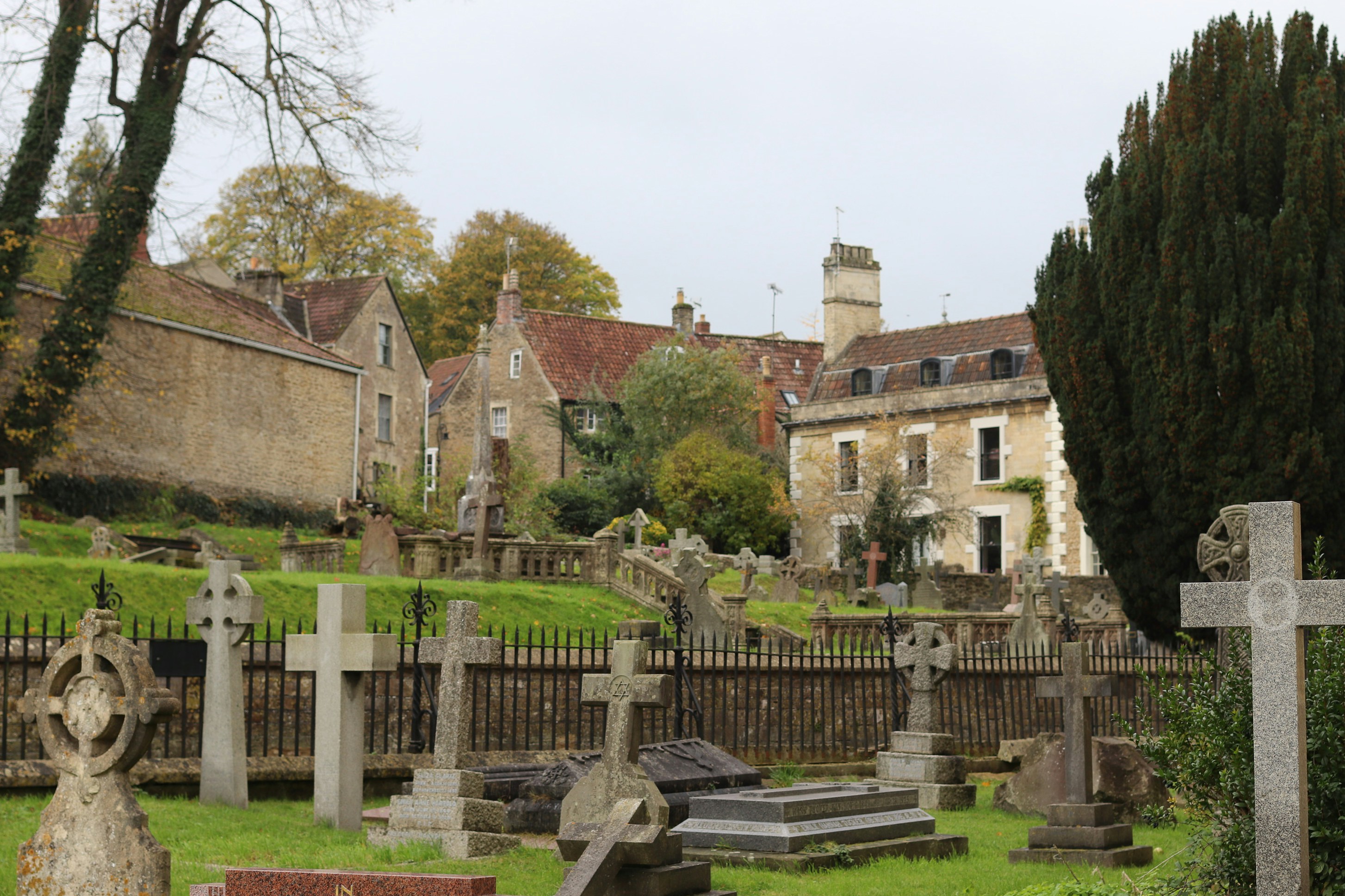 Ancient gravestones set against a backdrop of quaint buildings and lush greenery, evoking a sense of tranquility and reflection.