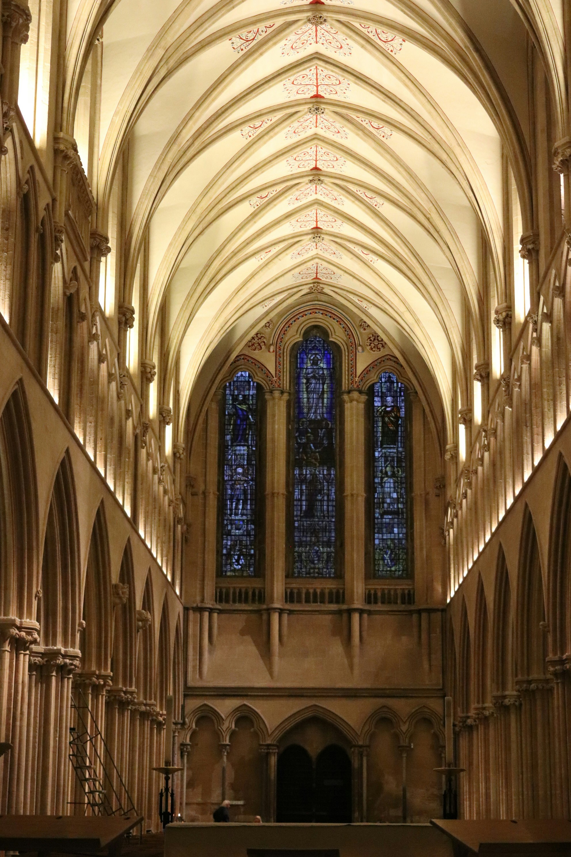 Illuminated Gothic architecture showcasing intricate arches and a grand stained glass window. The serene ambiance invites contemplation.