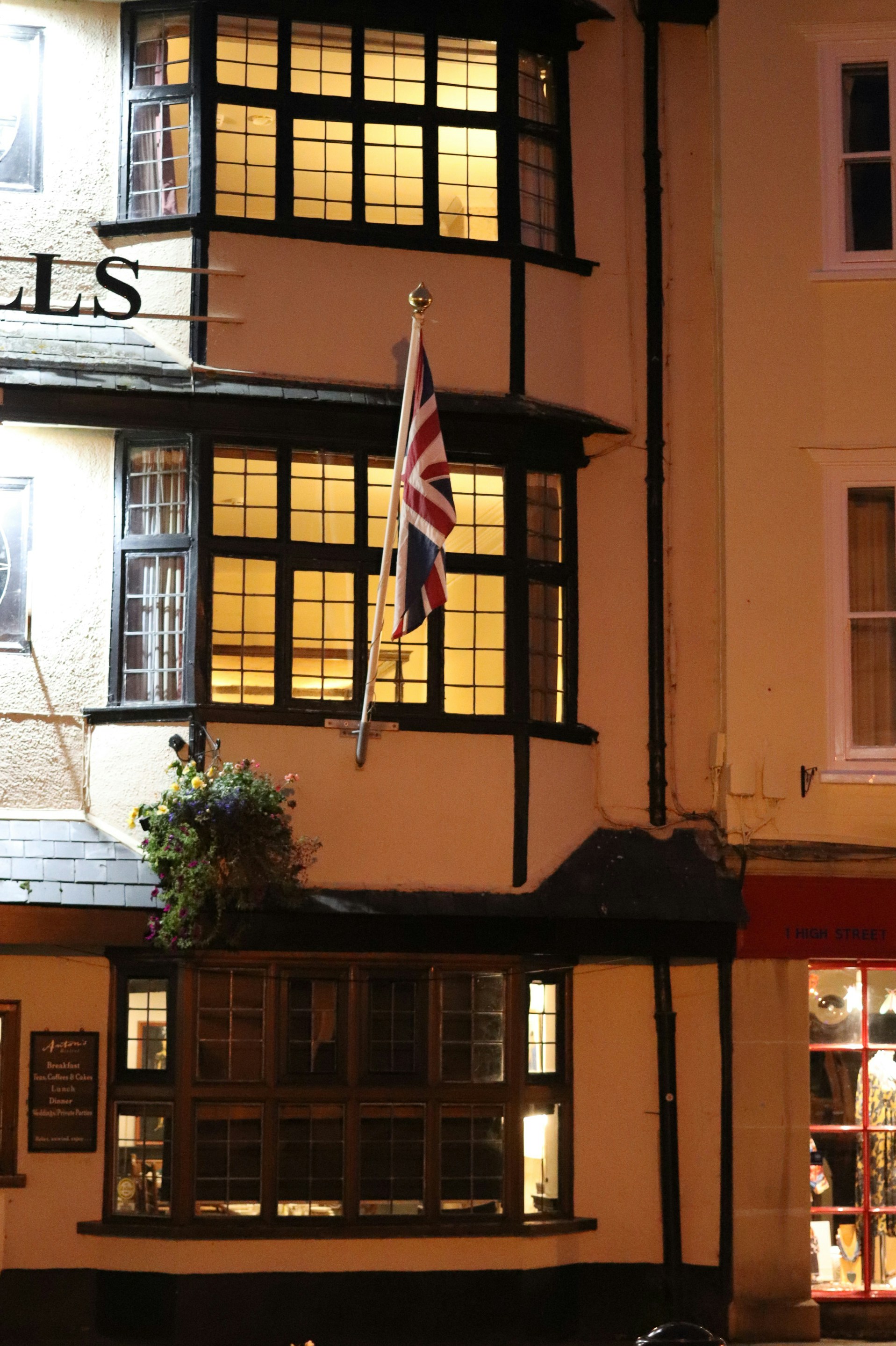 A traditional British pub facade adorned with a Union Jack, illuminated by warm lights, showcasing its historic architecture.