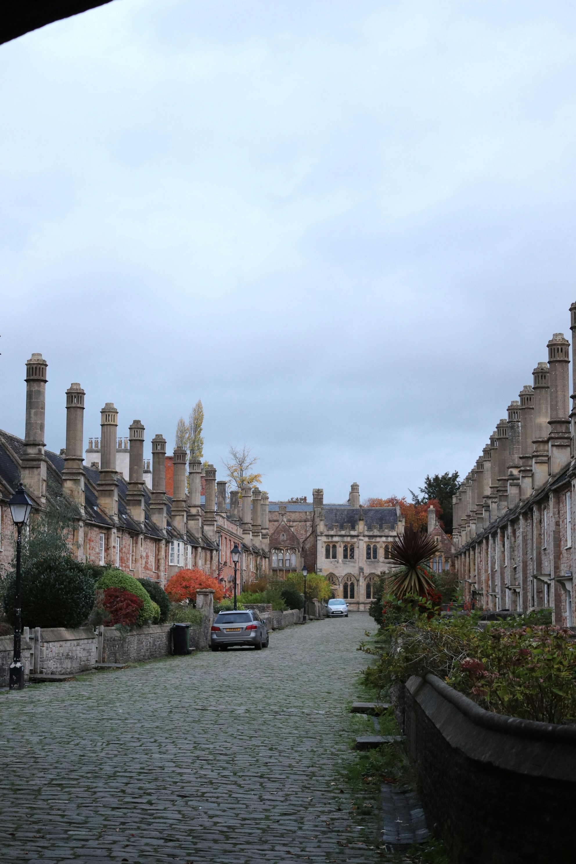 Charming cobblestone street lined with historic buildings and autumn foliage, leading to a distant architectural gem. The scene evokes a sense of nostalgia and tranquility.