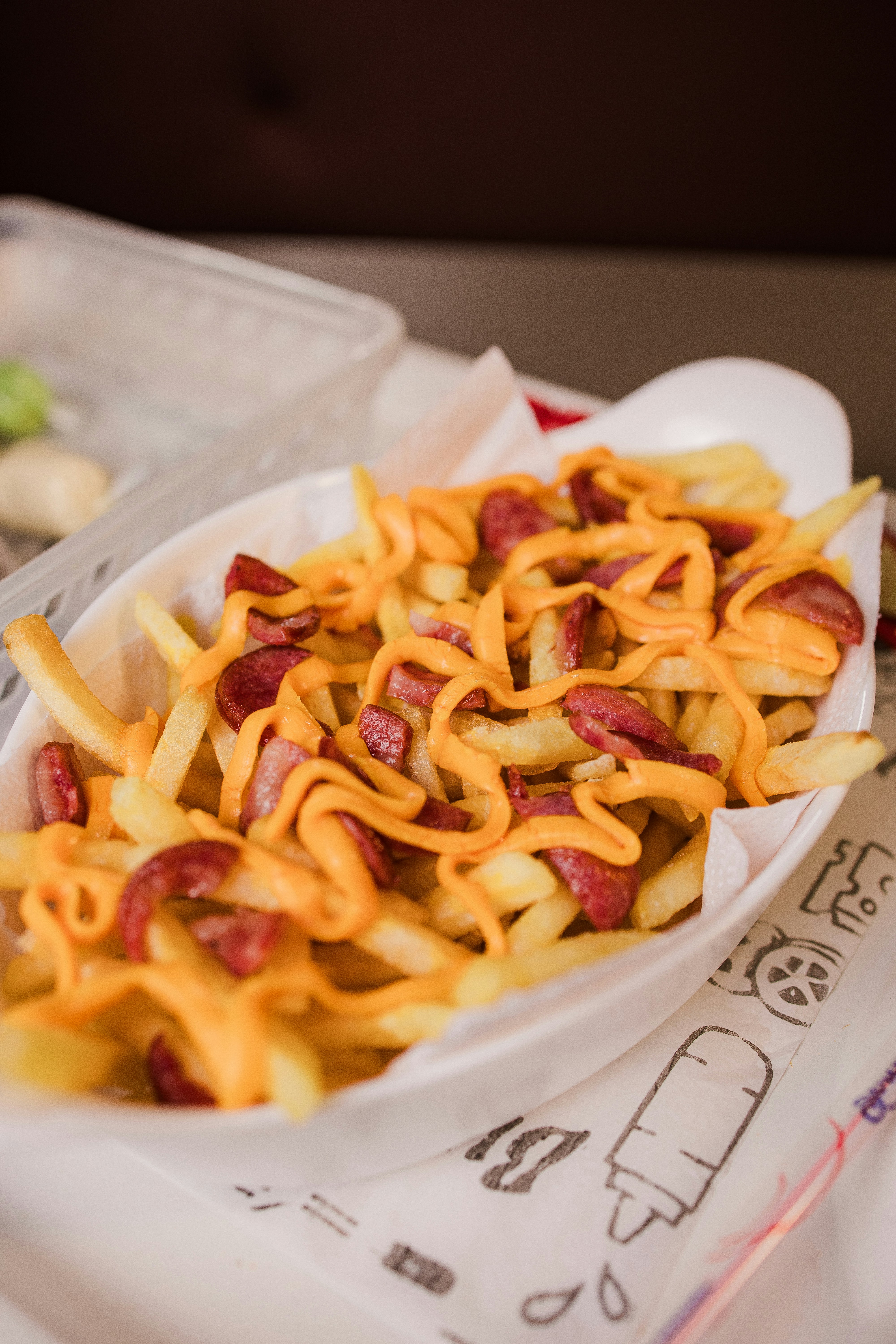 Orange Cheese Ribbons Draped Over Crispy Fries in a Takeout Boat