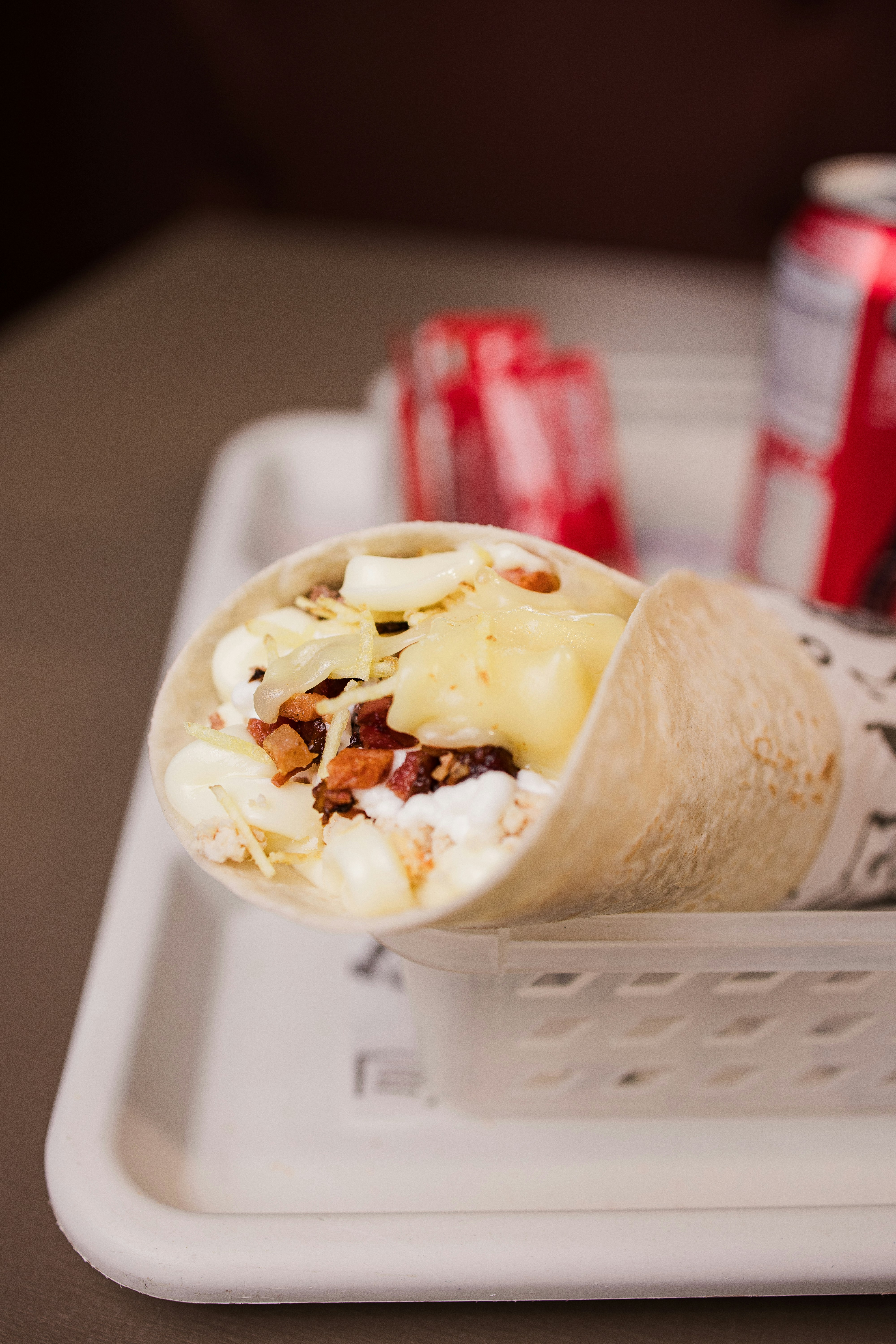 Edge of Crunch: a cheese-topped burrito end in a tray with red soda backdrop