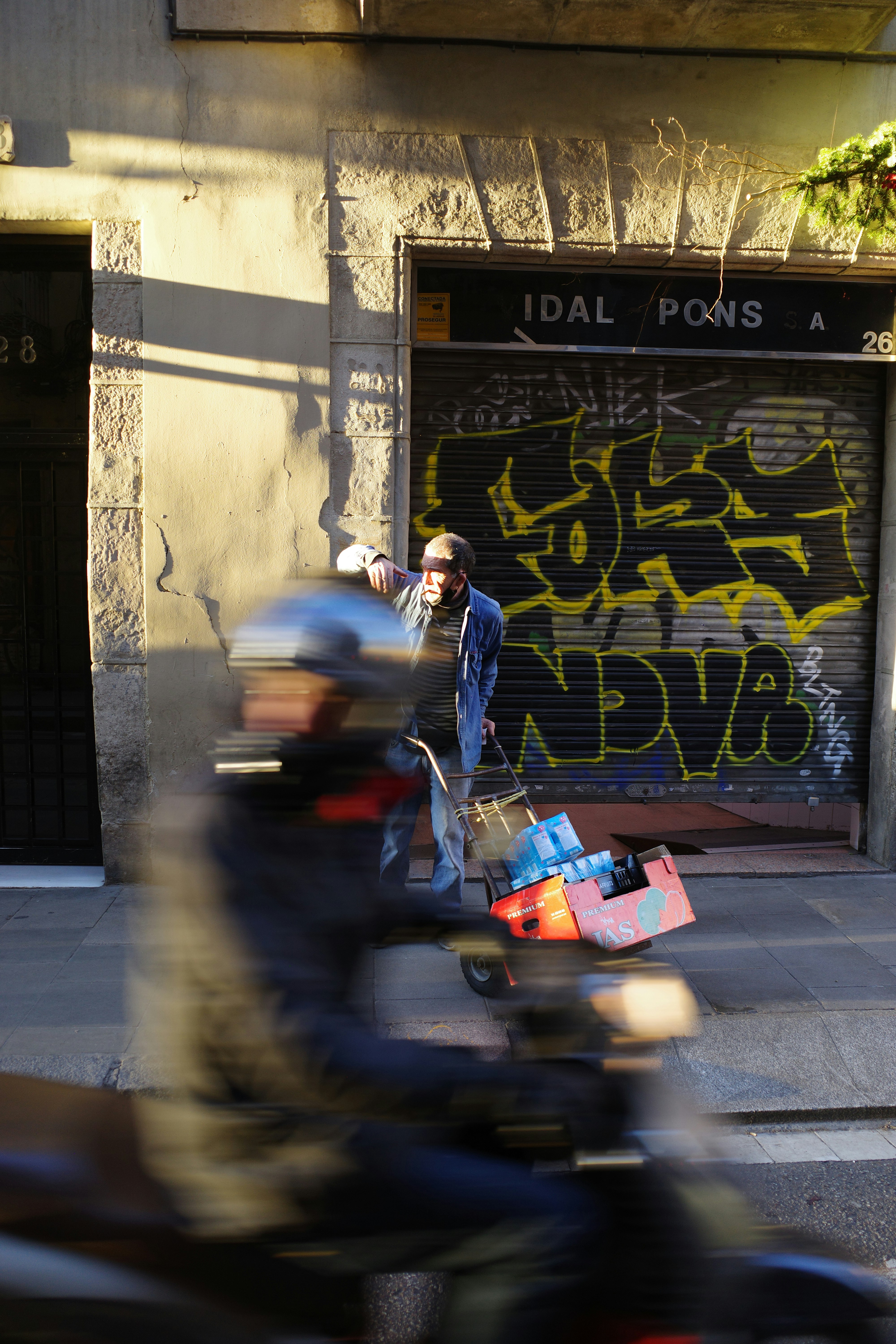 Man near graffiti-covered storefront with blurred motorcyclist photo ...