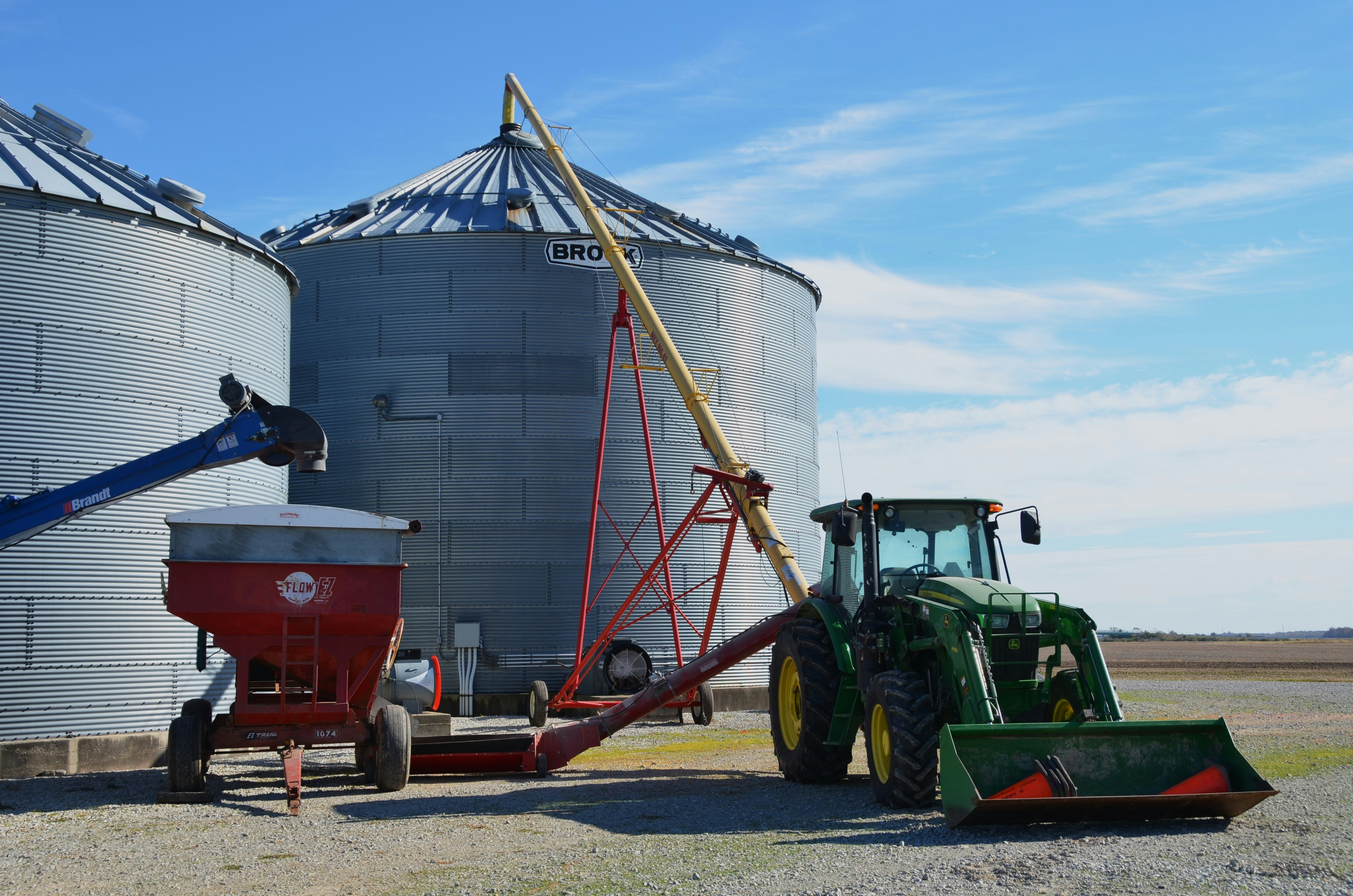 Diagonal Boom Over a Quiet Farmyard: Silos, Auger, and Tractor in Focus