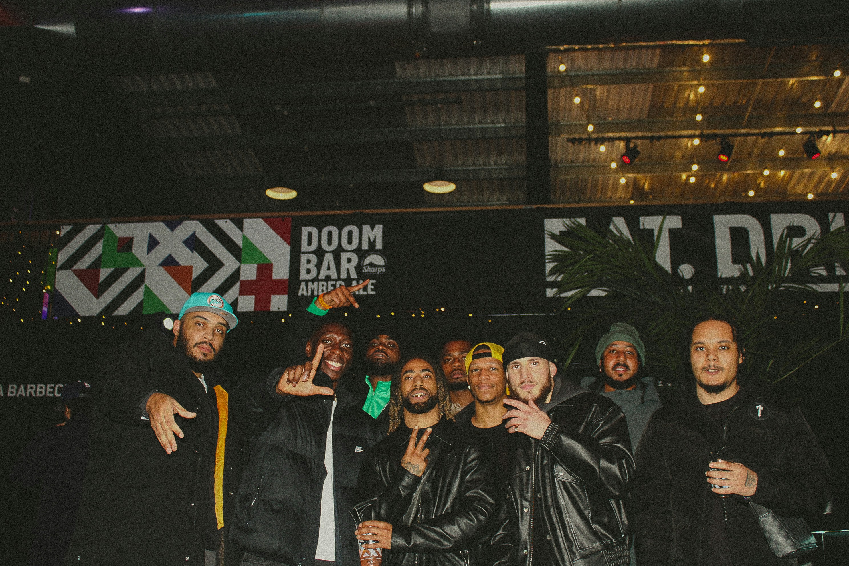 Group of friends posing together at Doom Bar, showcasing a lively atmosphere with vibrant decorations in the background.