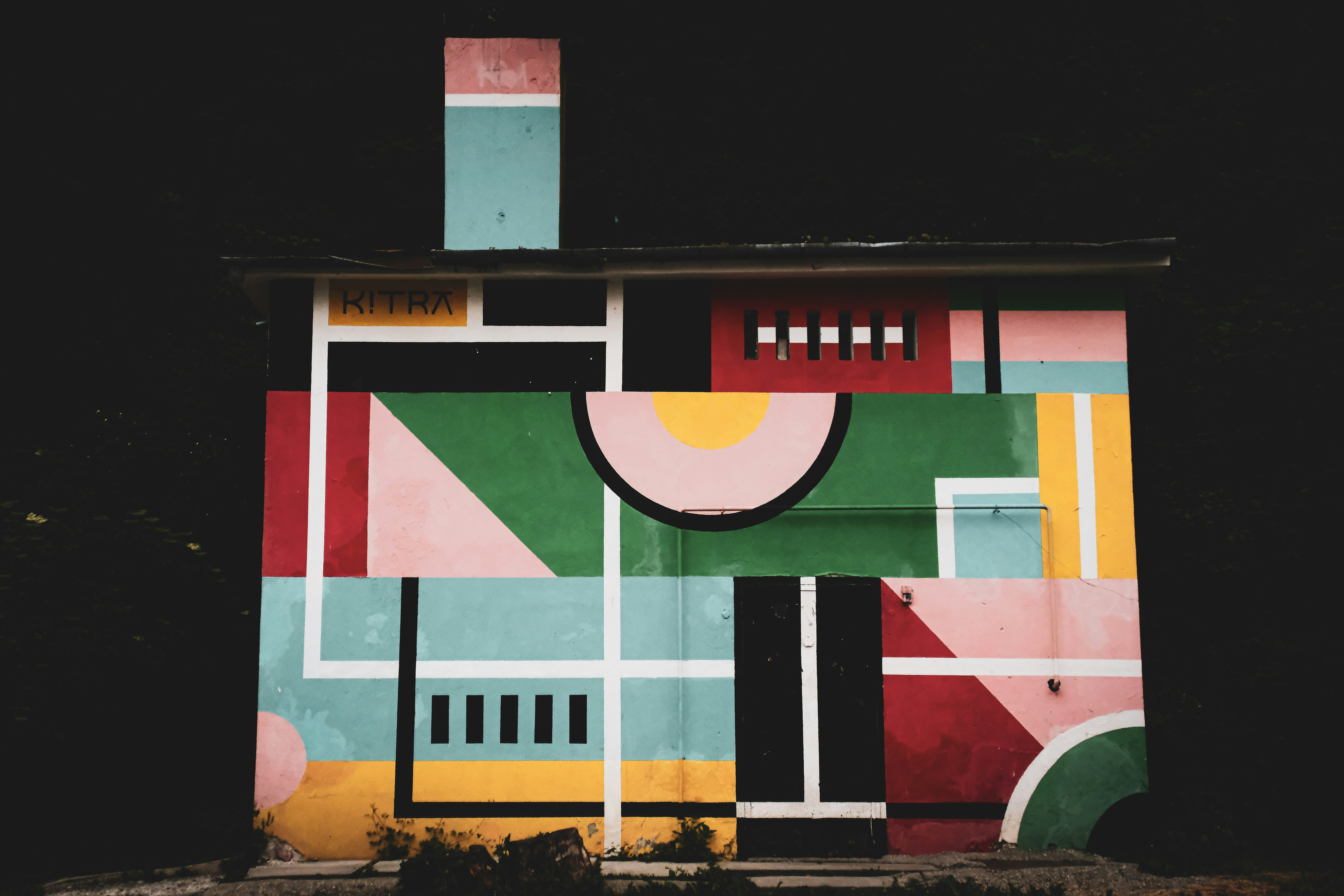 Vibrant mural featuring geometric shapes and bold colors on a building exterior. The artwork transforms the structure into an eye-catching urban landmark.