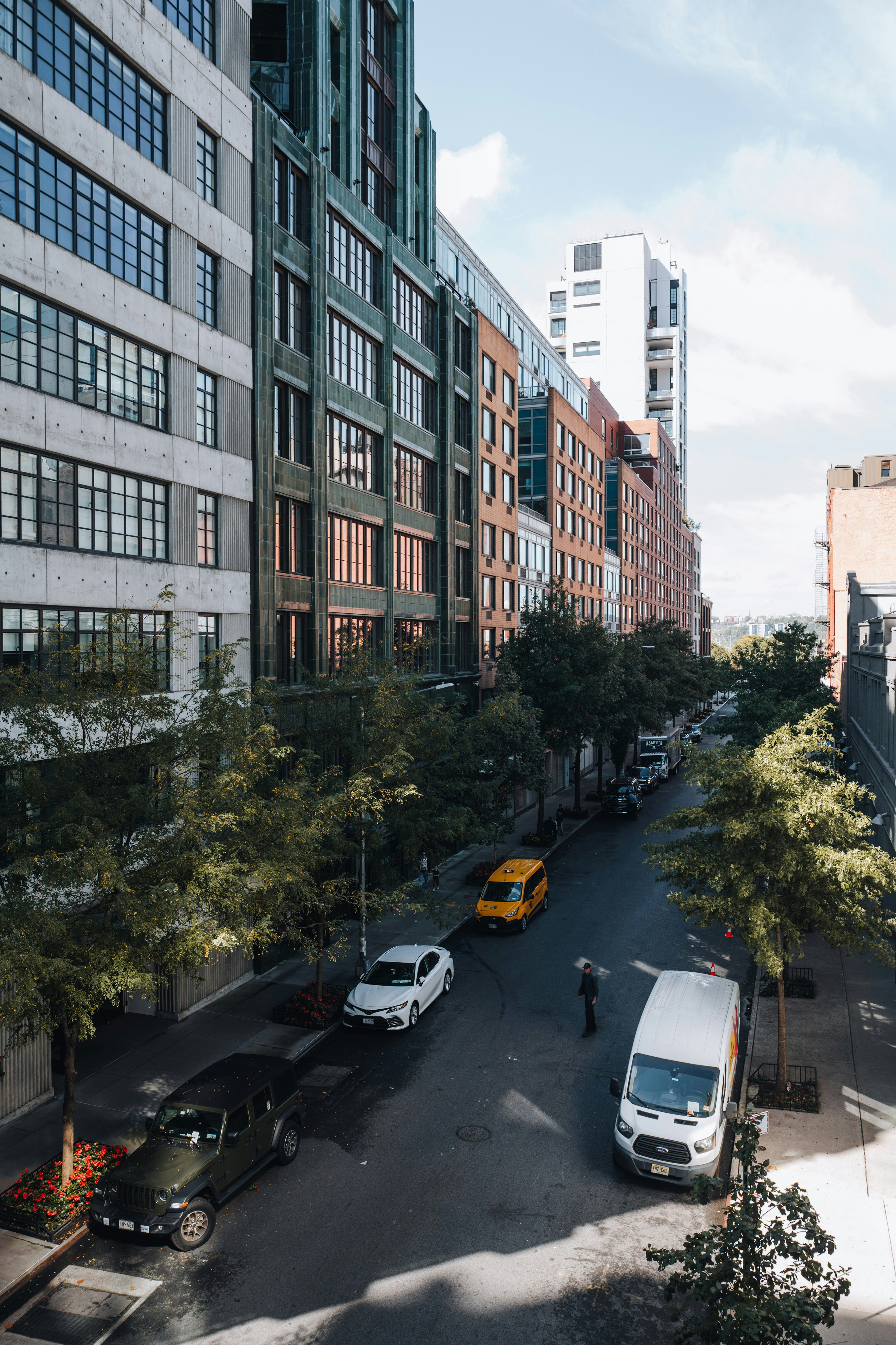 A quiet city street framed by modern architecture and lush trees, showcasing the blend of urban life and nature.
