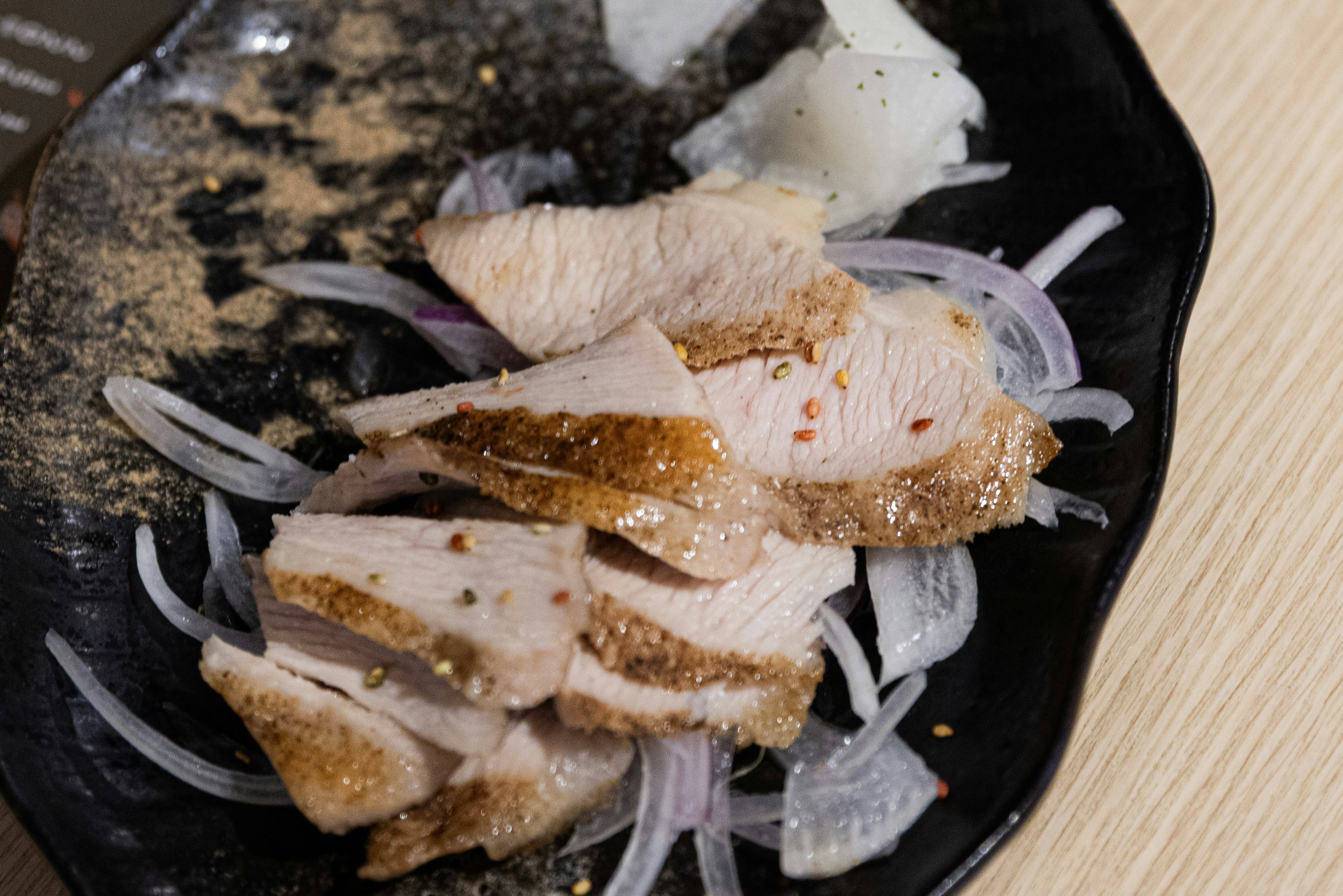 Glazed Pork Slices on Onion Ribbons: A Matte Black Plate Portrait