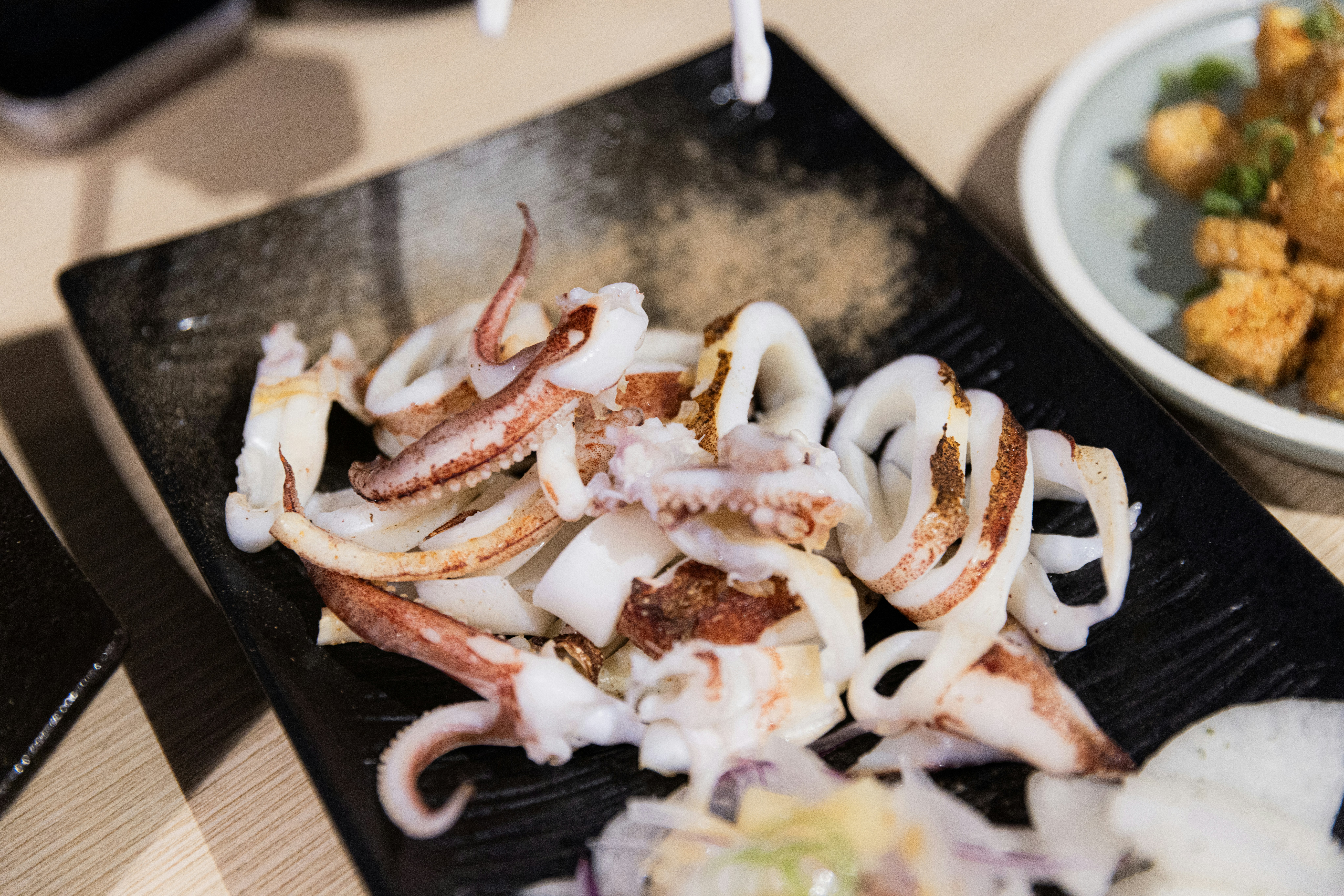 Cooked squid tentacles and rings on a black plate. photo – Free Seafood ...