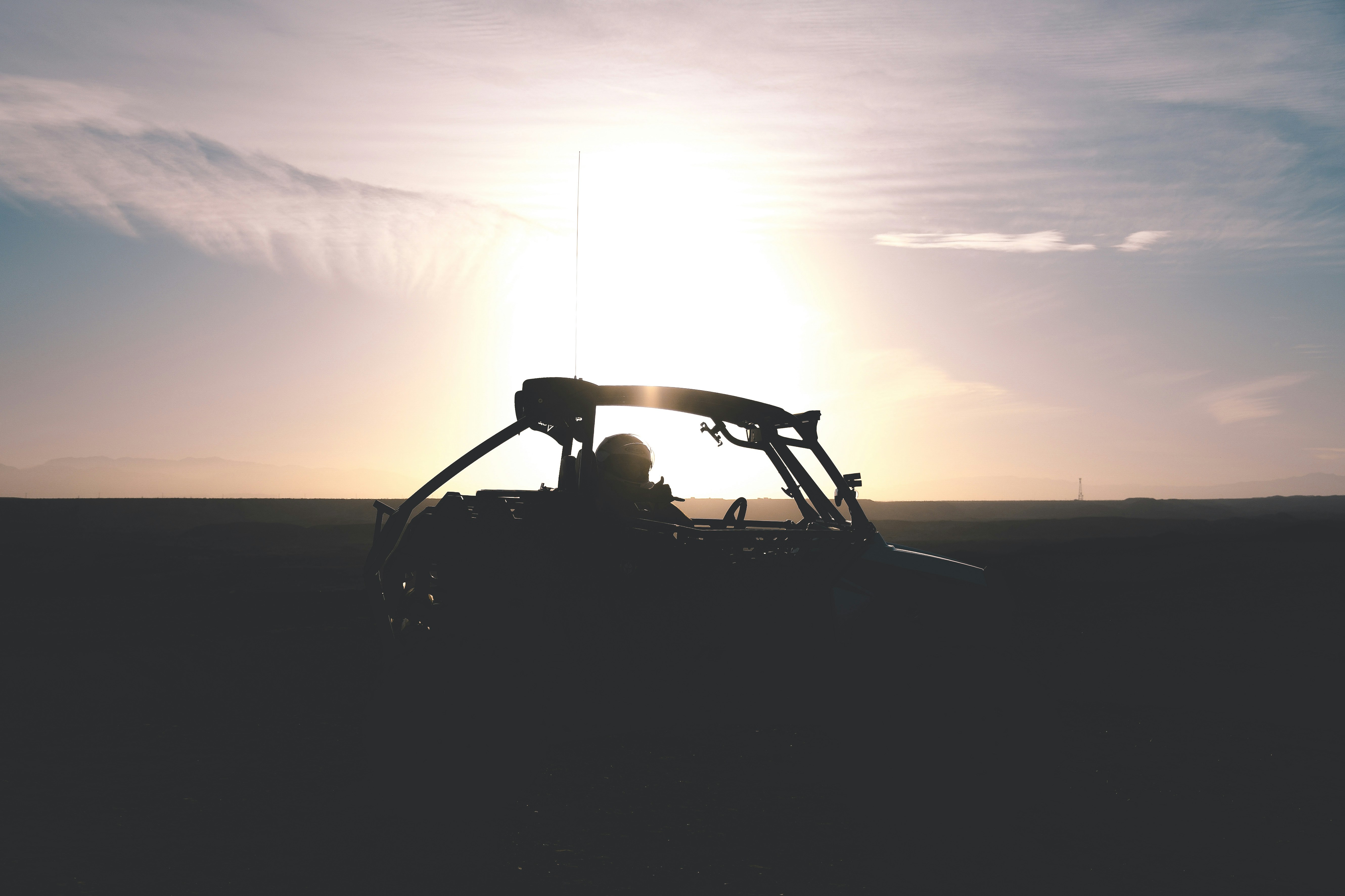 Silhouette of an off-road vehicle against a vibrant sunset, highlighting the thrill of exploration. The expansive landscape sets the stage for adventure.