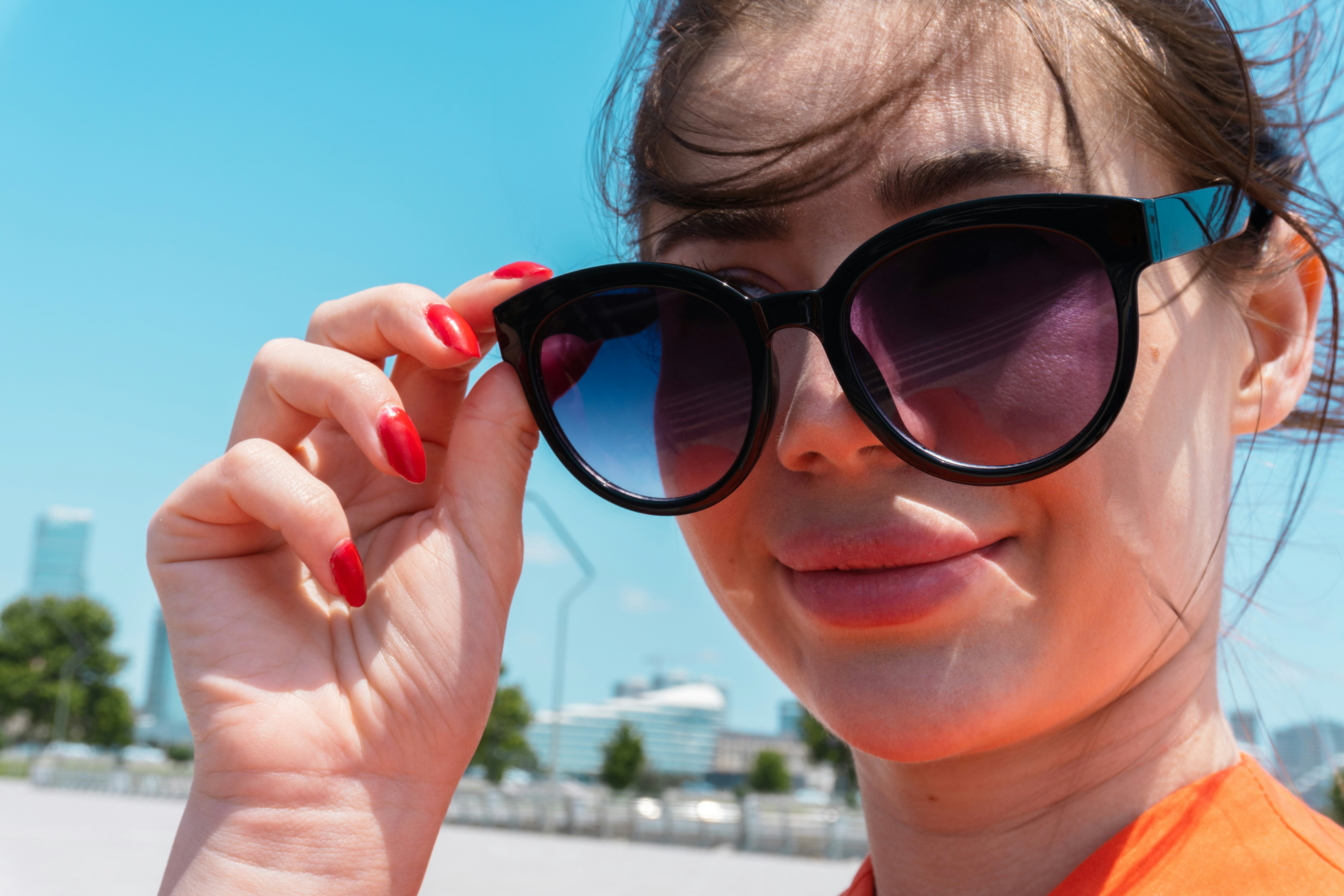 Orange Moments: Bold Sunglasses and Red Nails in a Sunlit Portrait