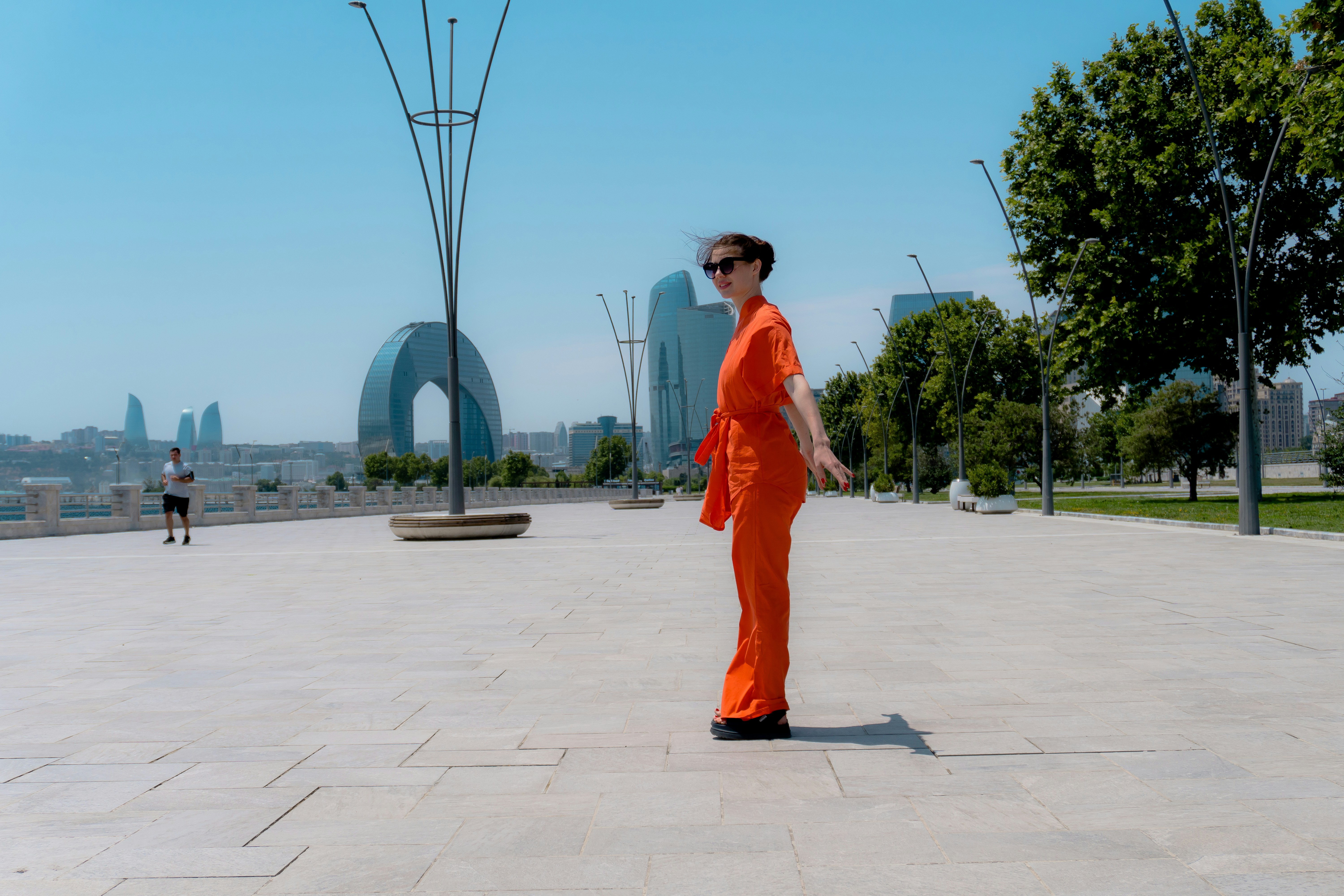 Orange-clad figure anchors a sunlit plaza with a futuristic cityscape