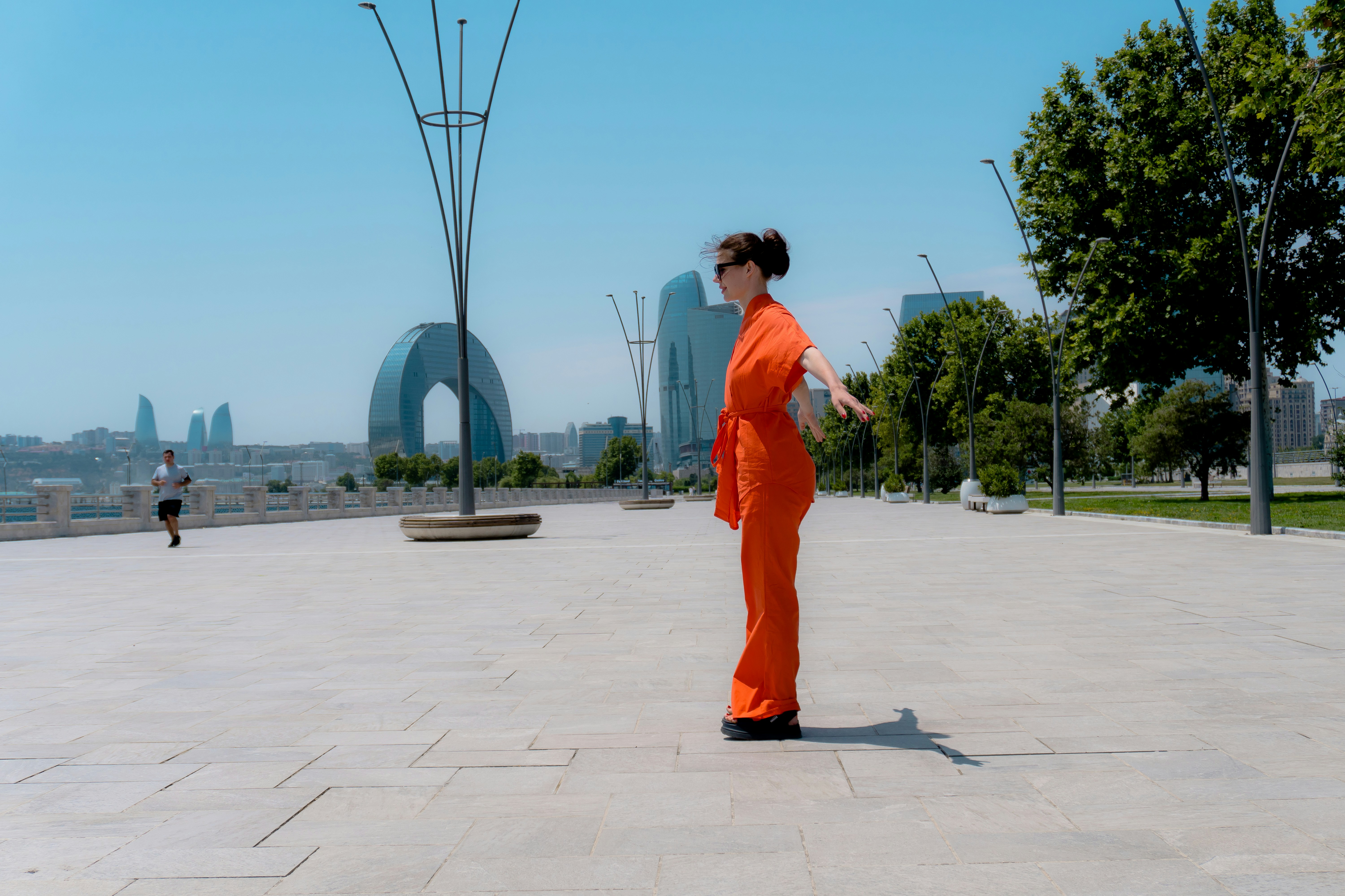 Orange Ensemble on a Sunlit Promenade Against a Futuristic Cityscape