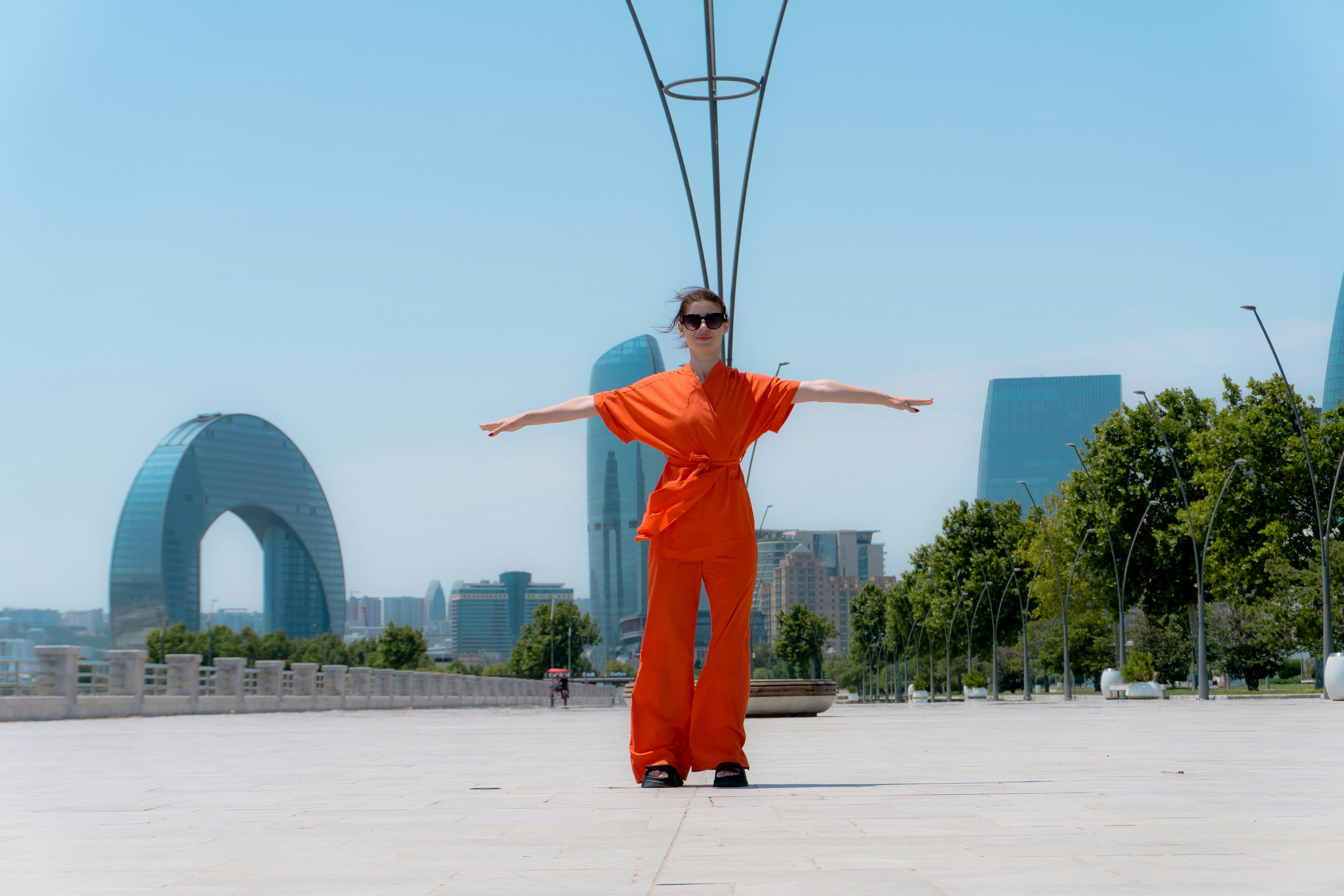Outstretched in Orange: A Solo Gesture Against a Modern Skyline