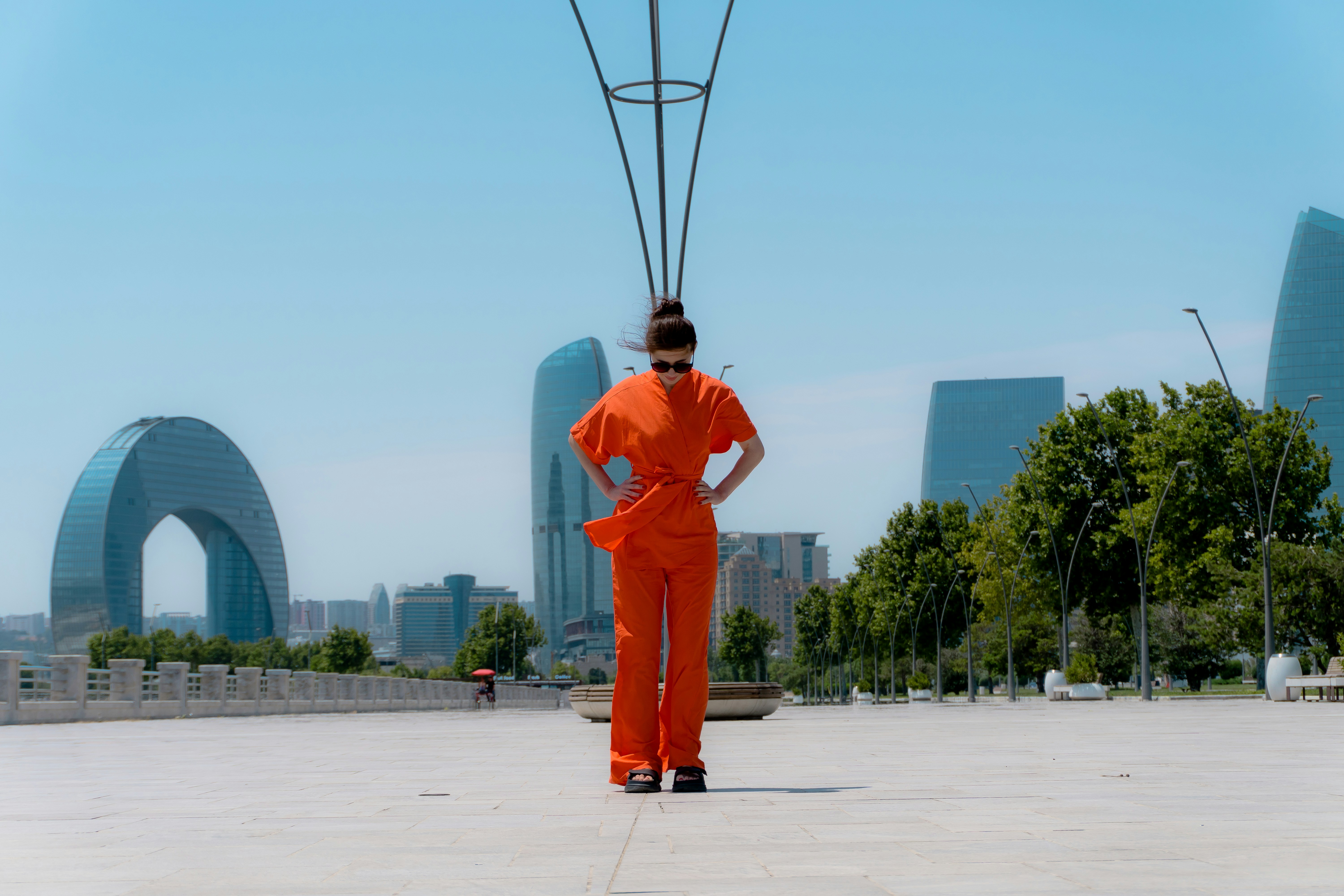 Orange-Clad Figure Stands Boldly on a Wide Plaza Under a Futuristic City Skyline