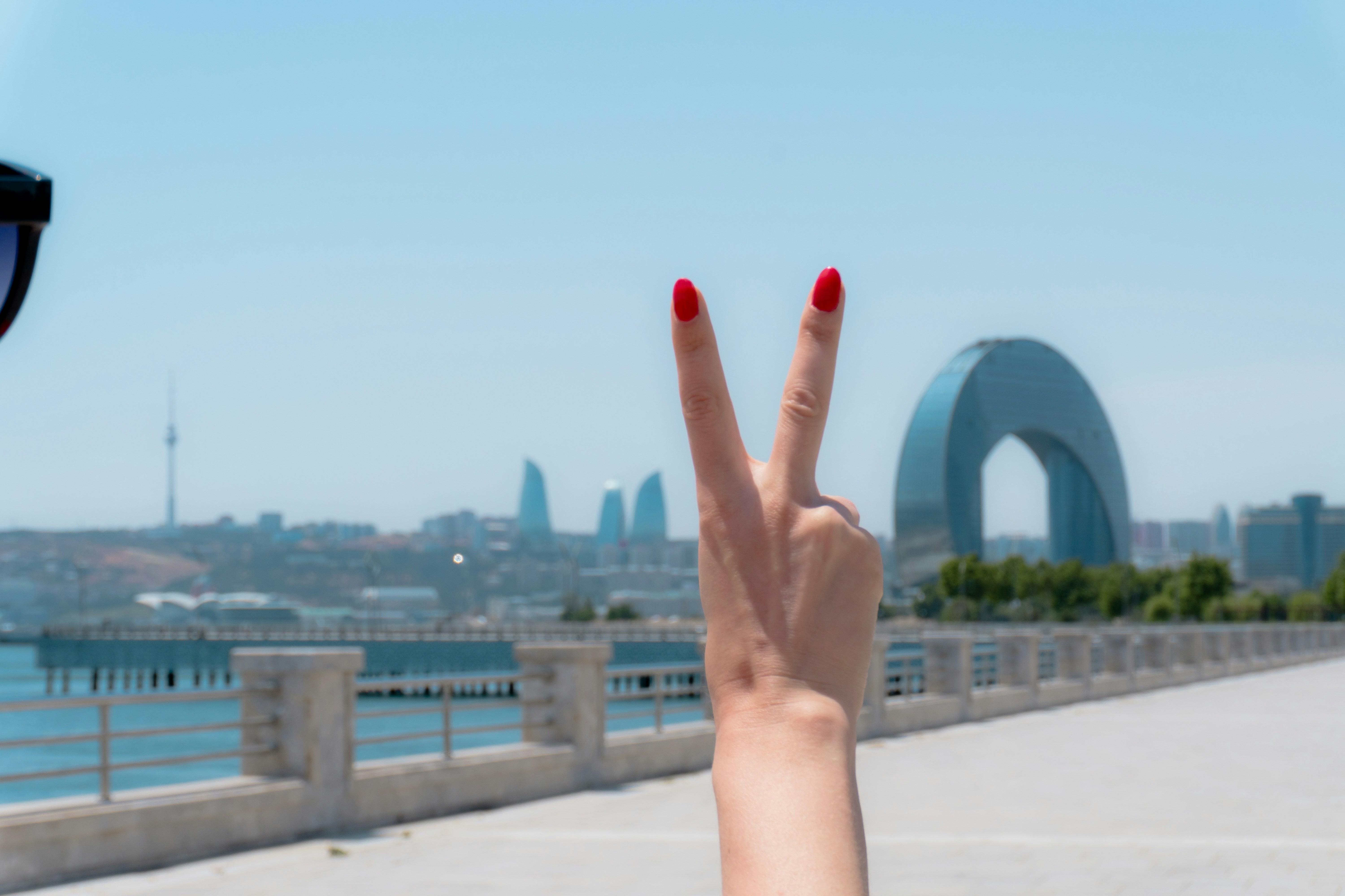 V‑Sign by the Waterfront: Palm-Pressed Confidence Against a City Skyline
