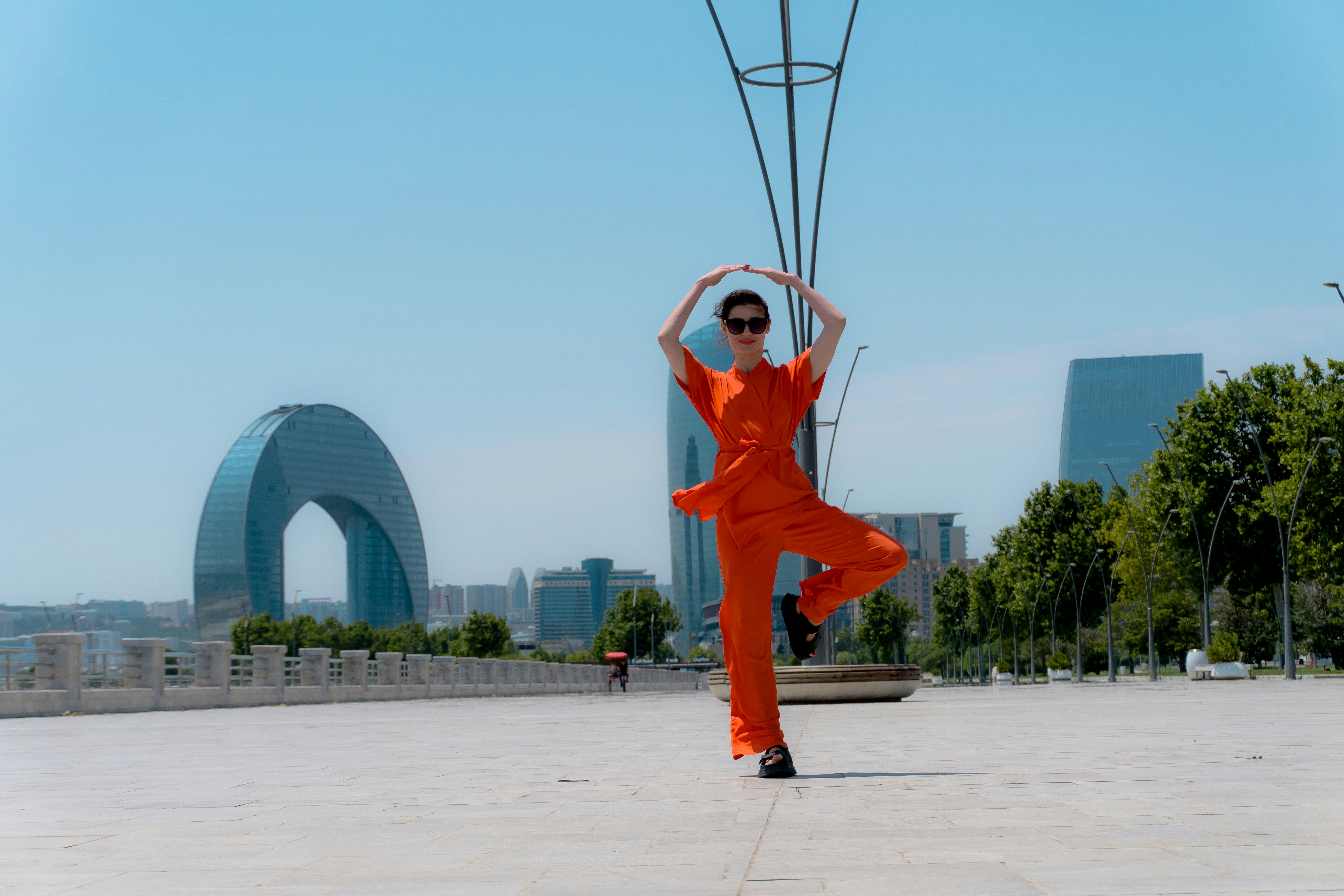 Balance in Orange: A Dancer in a Sunlit Plaza Amid Futuristic Arches