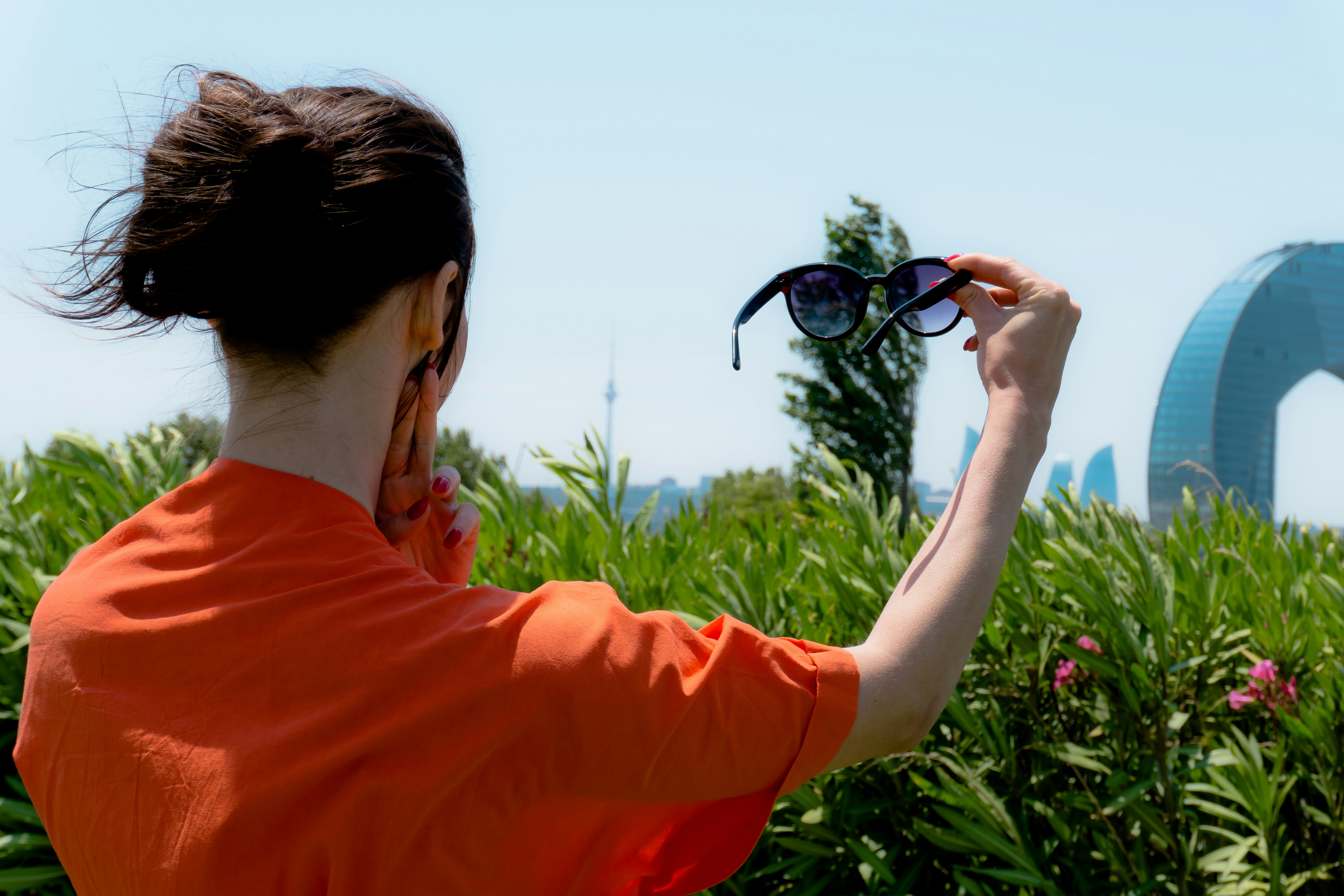 Edge of Shade: Holding Sunglasses in a Sunlit City Garden