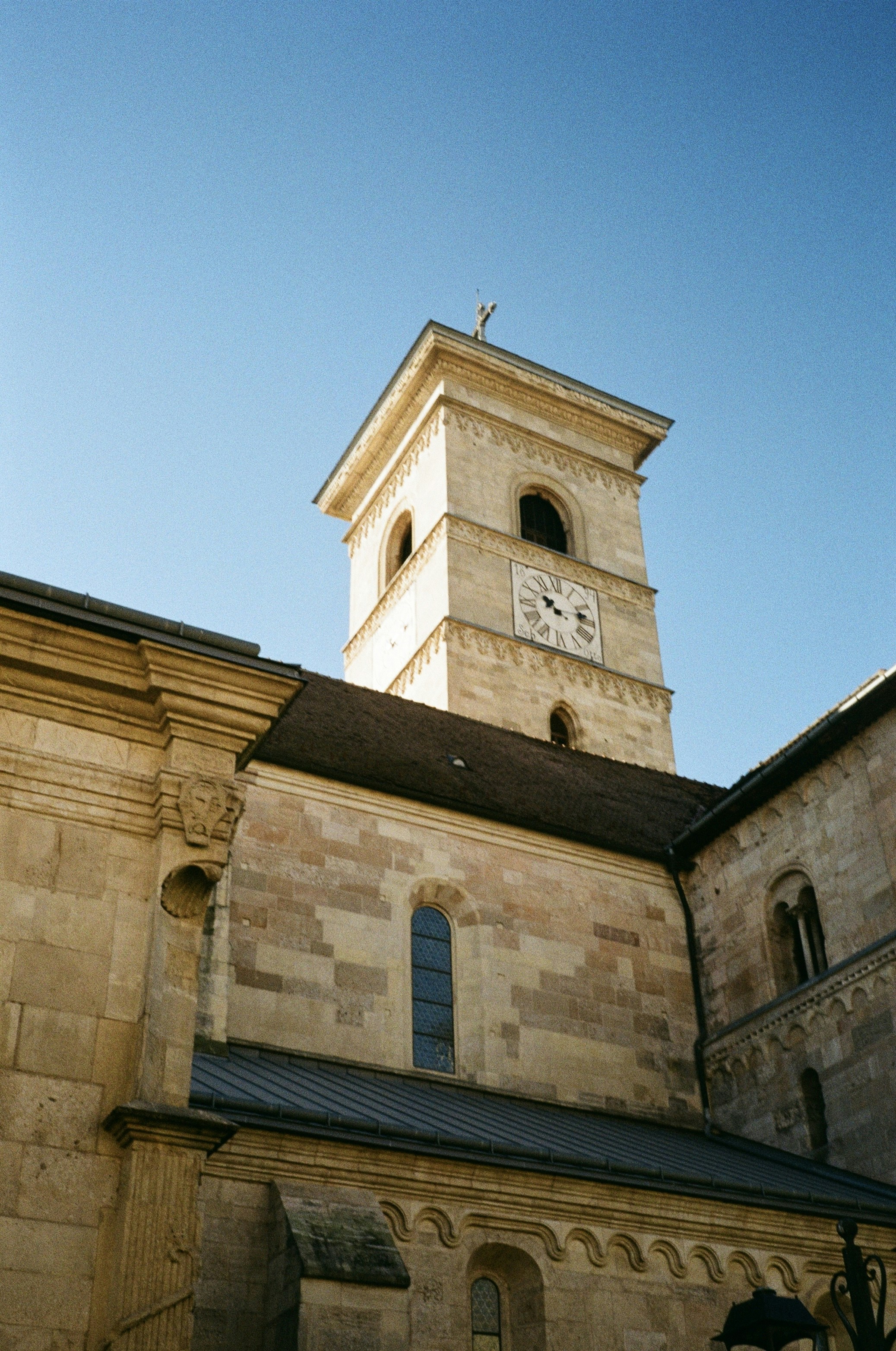 Stone church tower with clock against blue sky