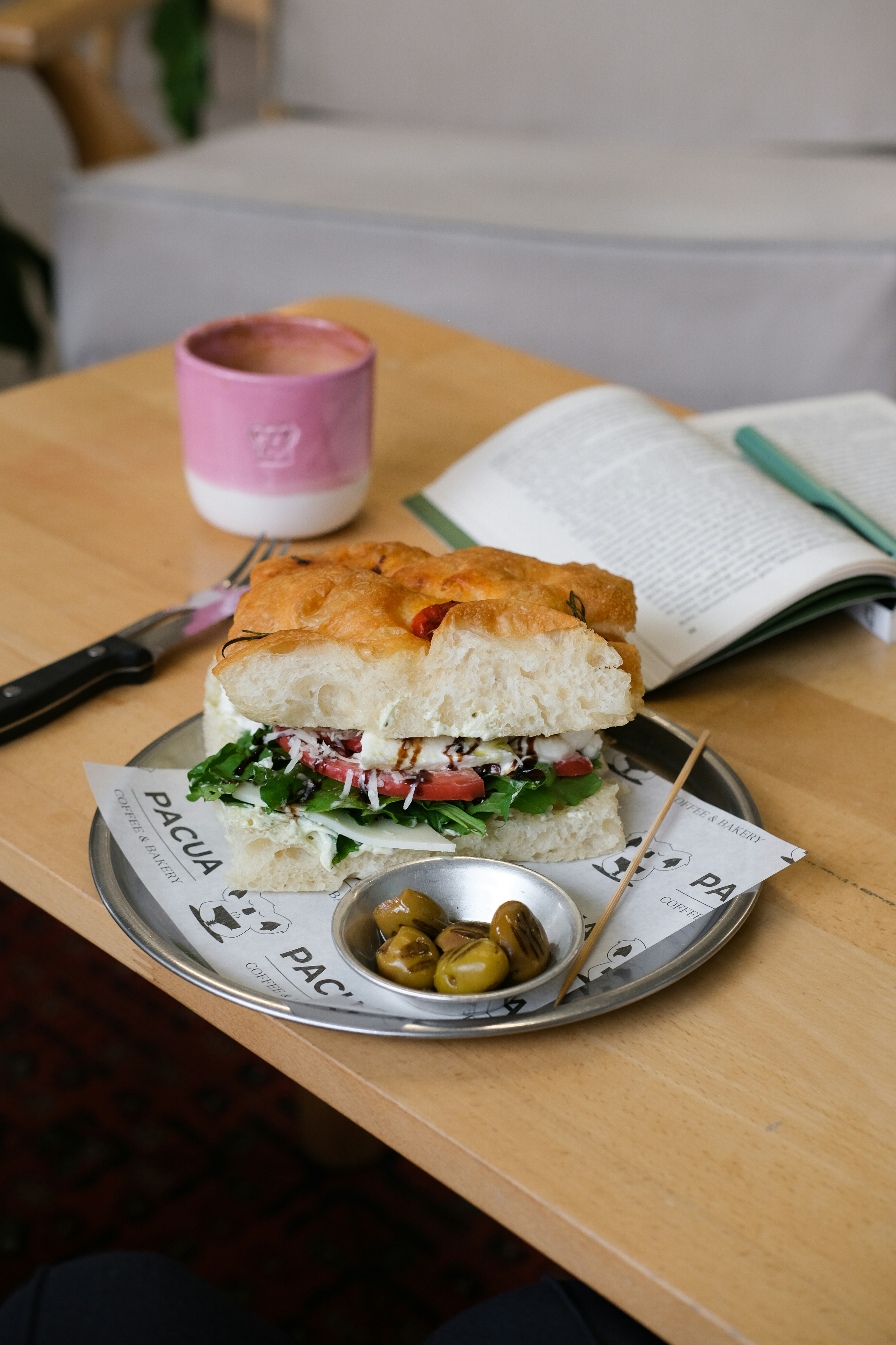 Crusty Bun Summit: Greens and Tomatoes with Olives on a Café Plate
