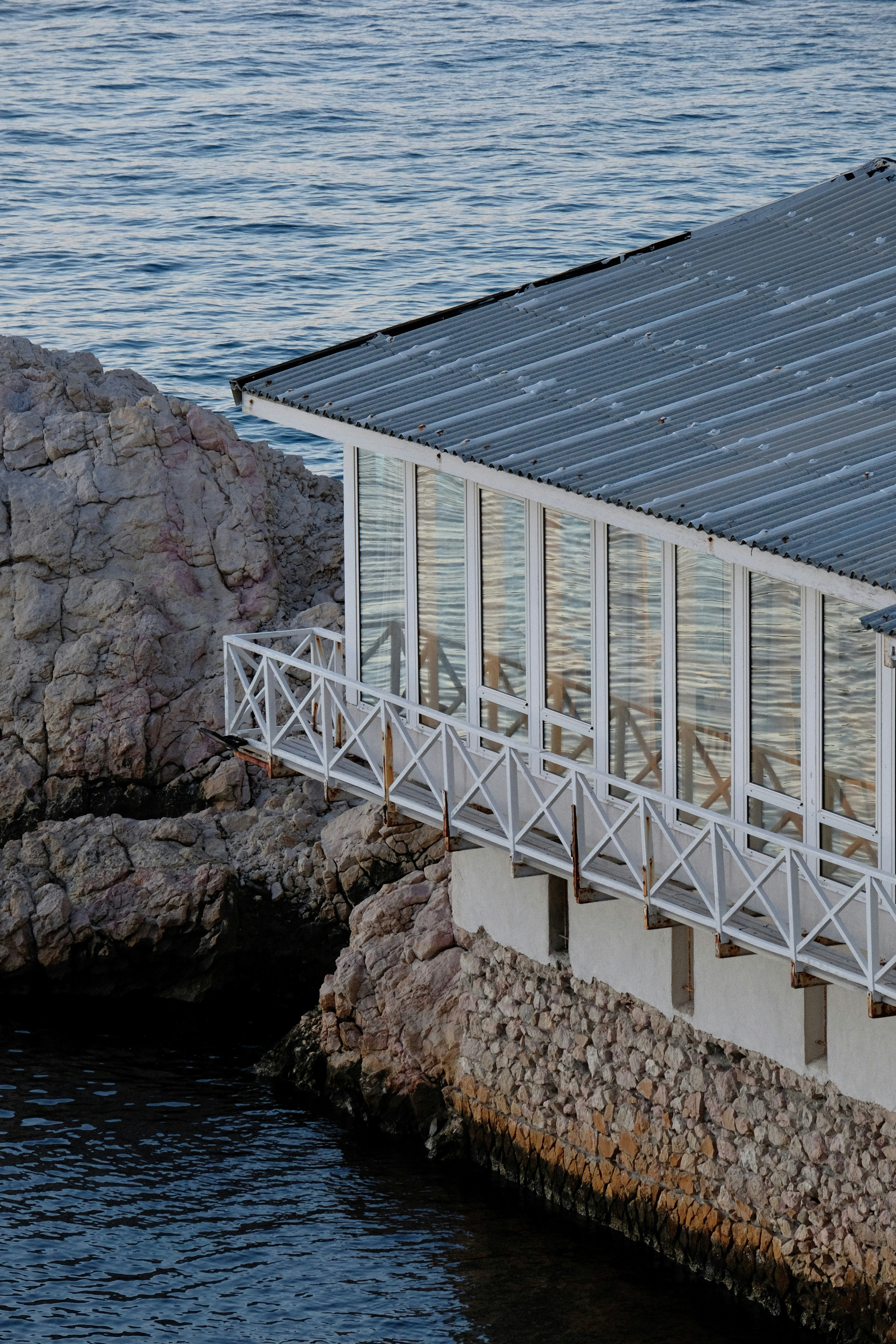 Glass-Walled Seaside Shelter Rising from Rugged Rocks