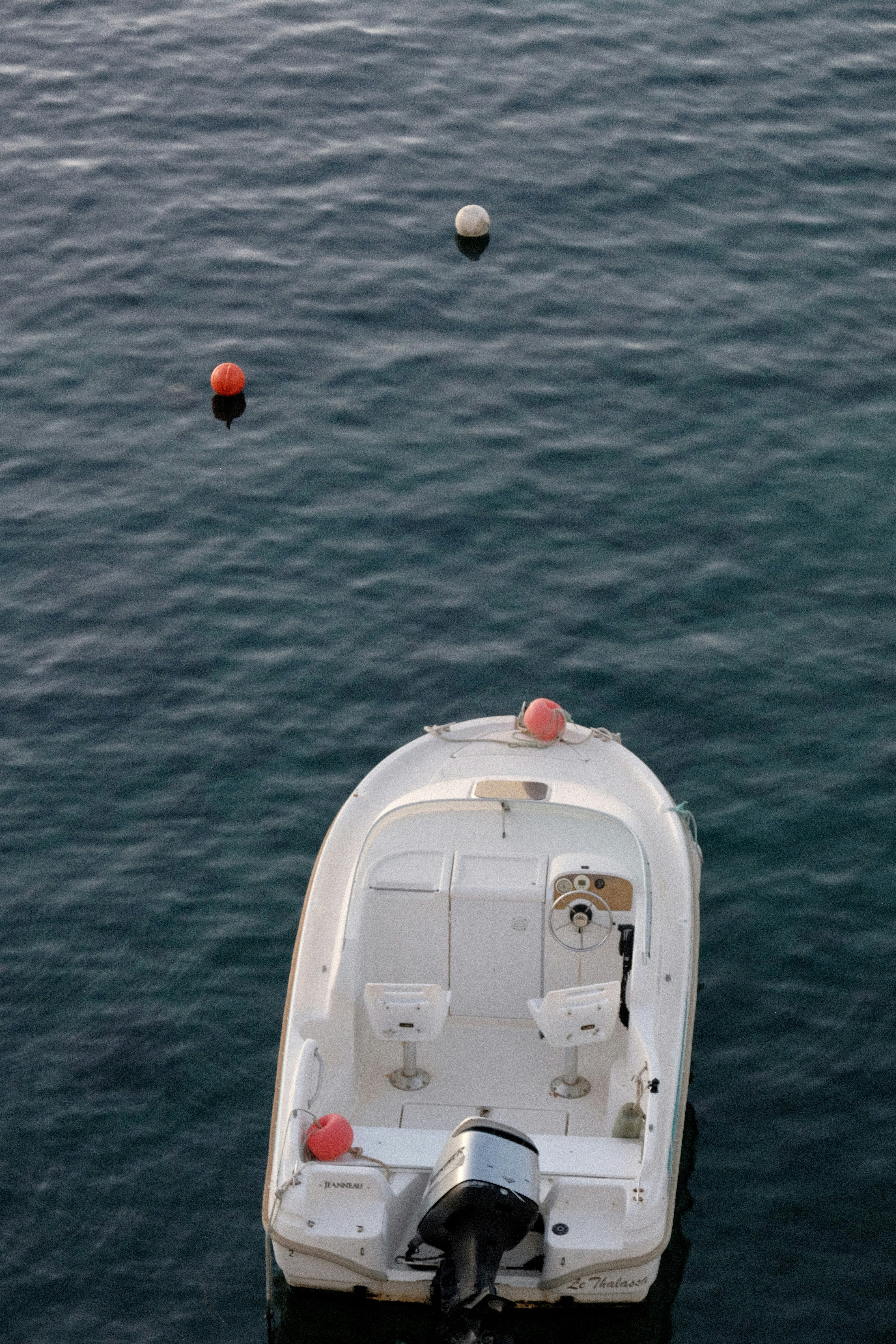 Azure Solitude: A White Tender Anchored Among Quiet Buoys