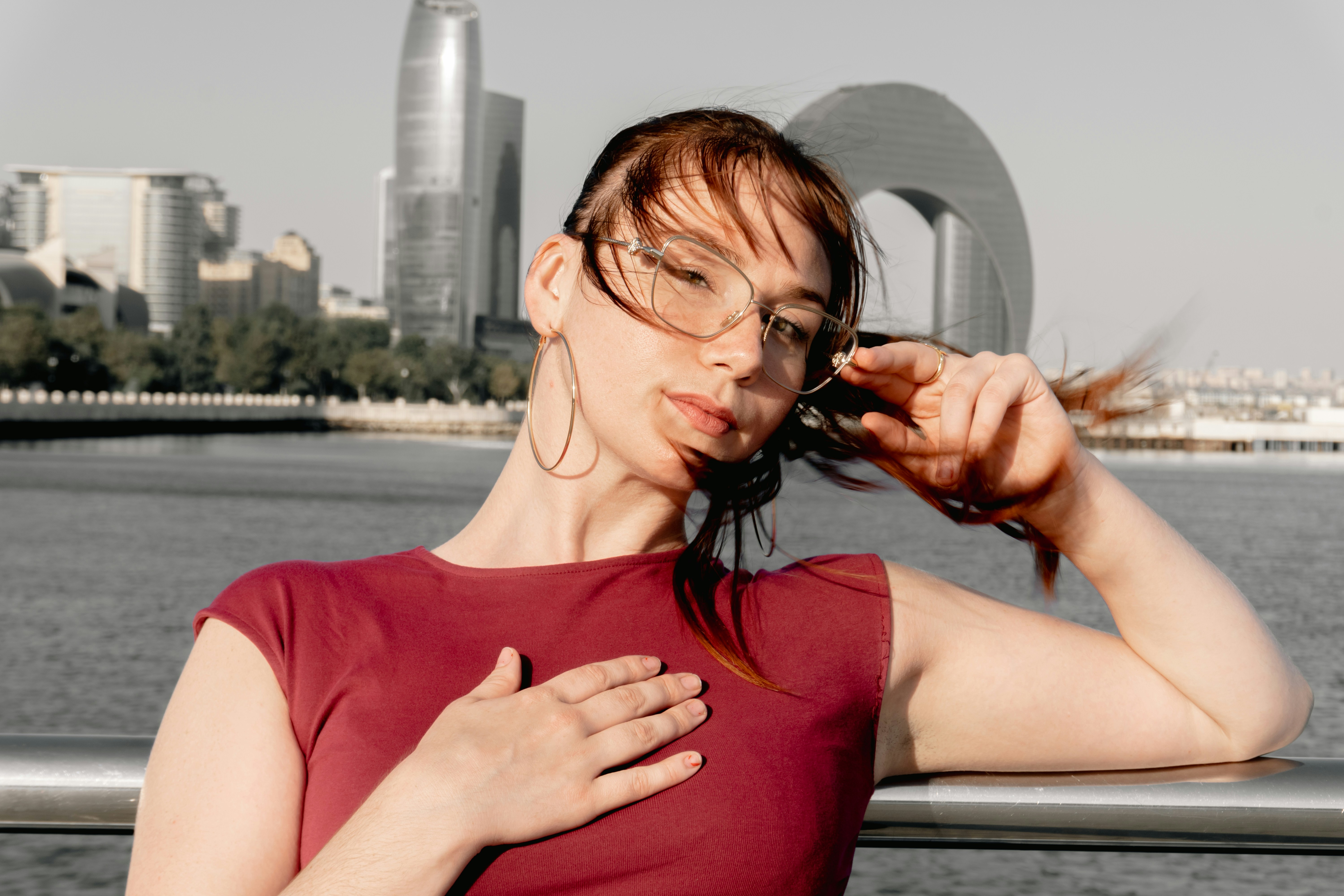 Wind-Swept Portrait by the Waterfront: A Burgundy Moment Against the Cityscape