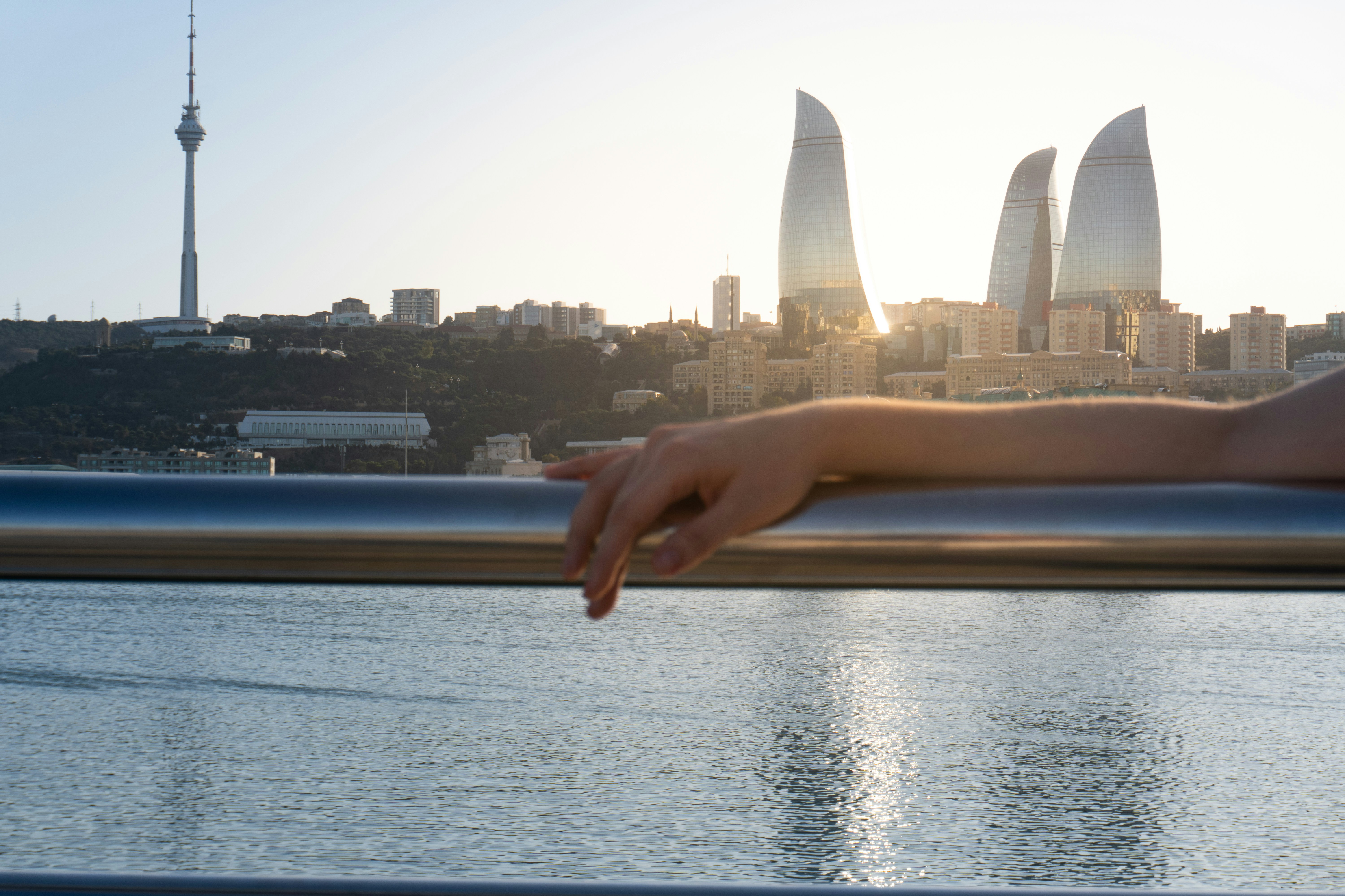 Golden hour over Baku: a hand resting on a railing with the Flame Towers in profile