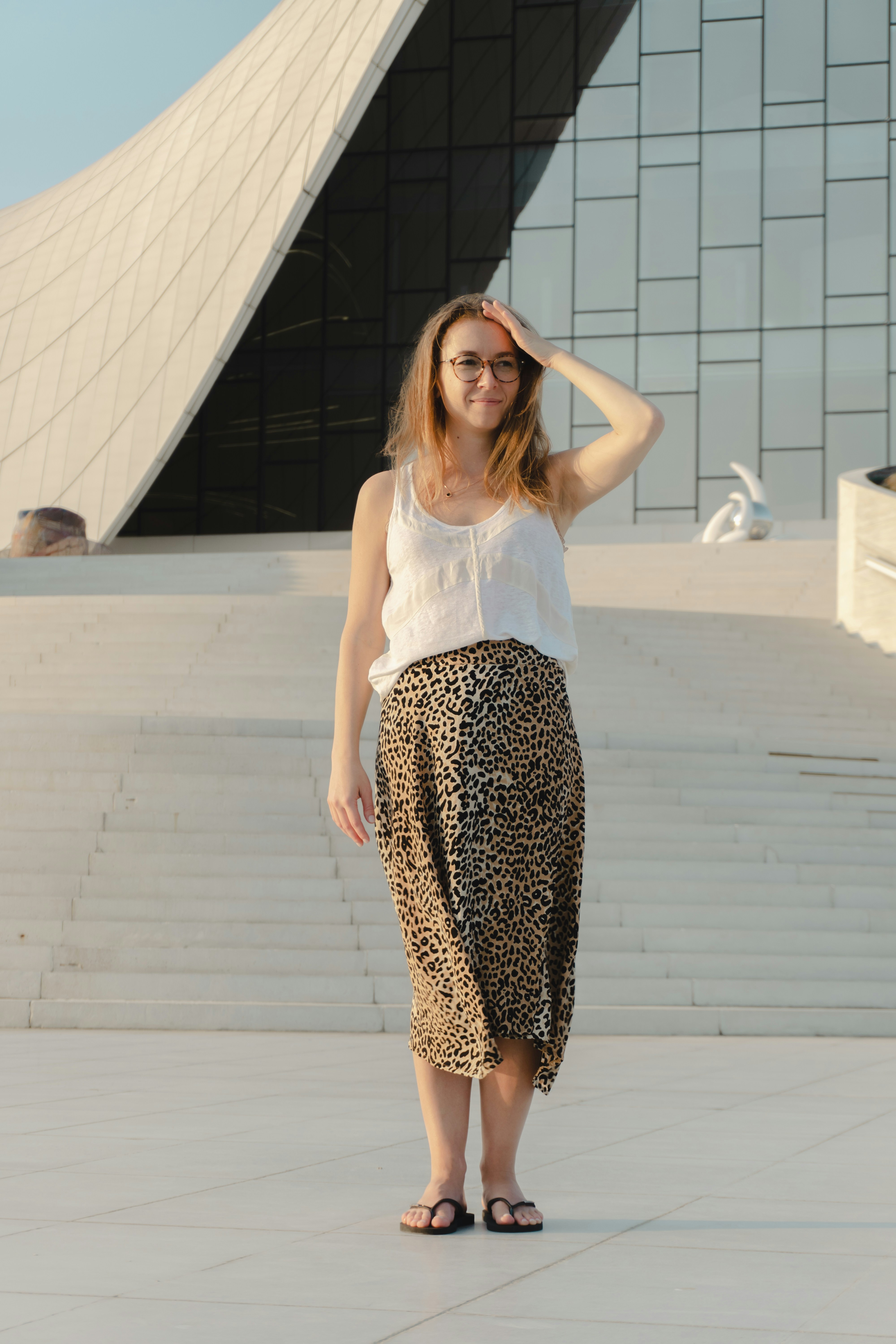 Portrait on Terrace: Woman in White Tank and Leopard Skirt Amid Modern Architecture