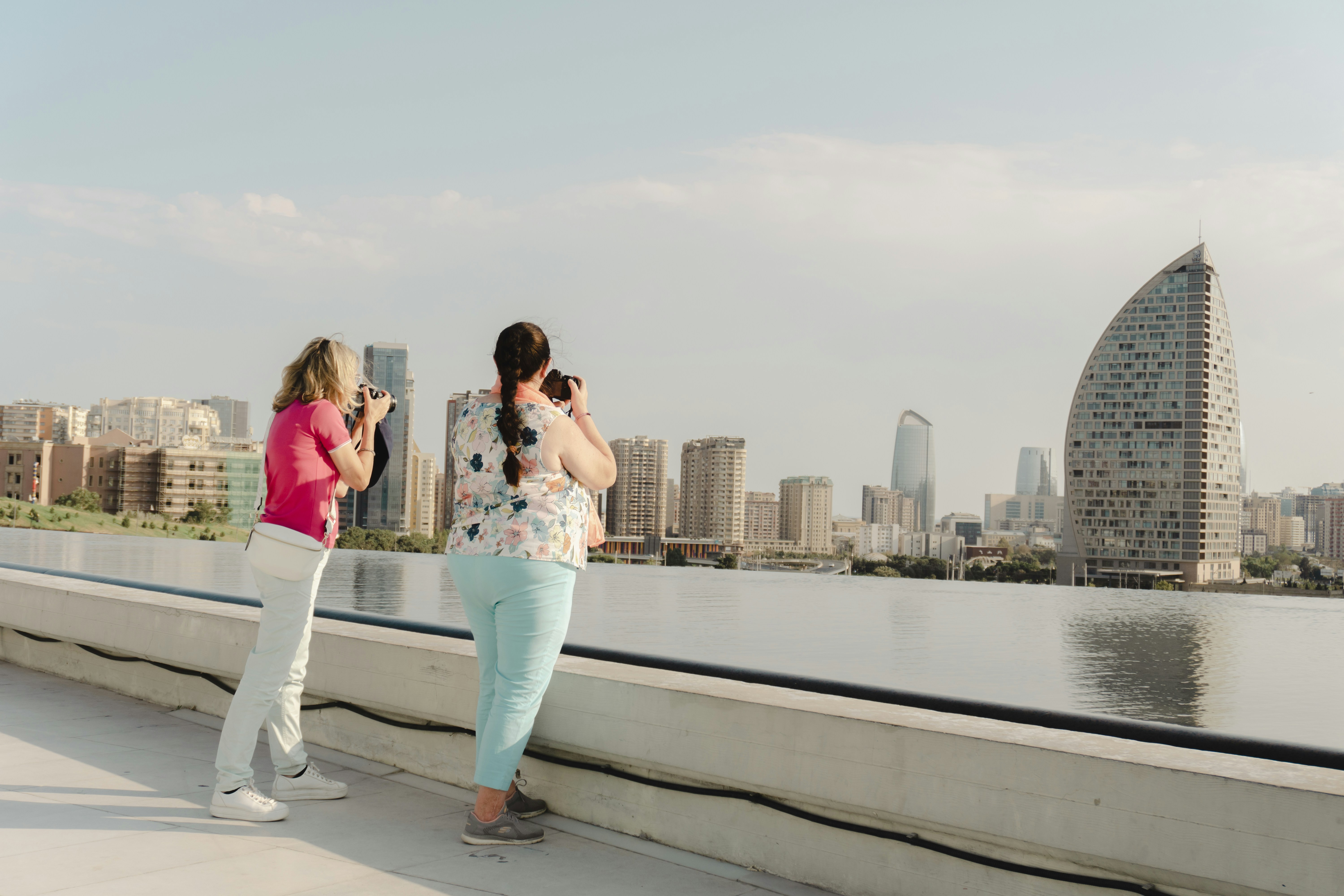 Two photographers by the bridge capture a skyline with a sculptural building