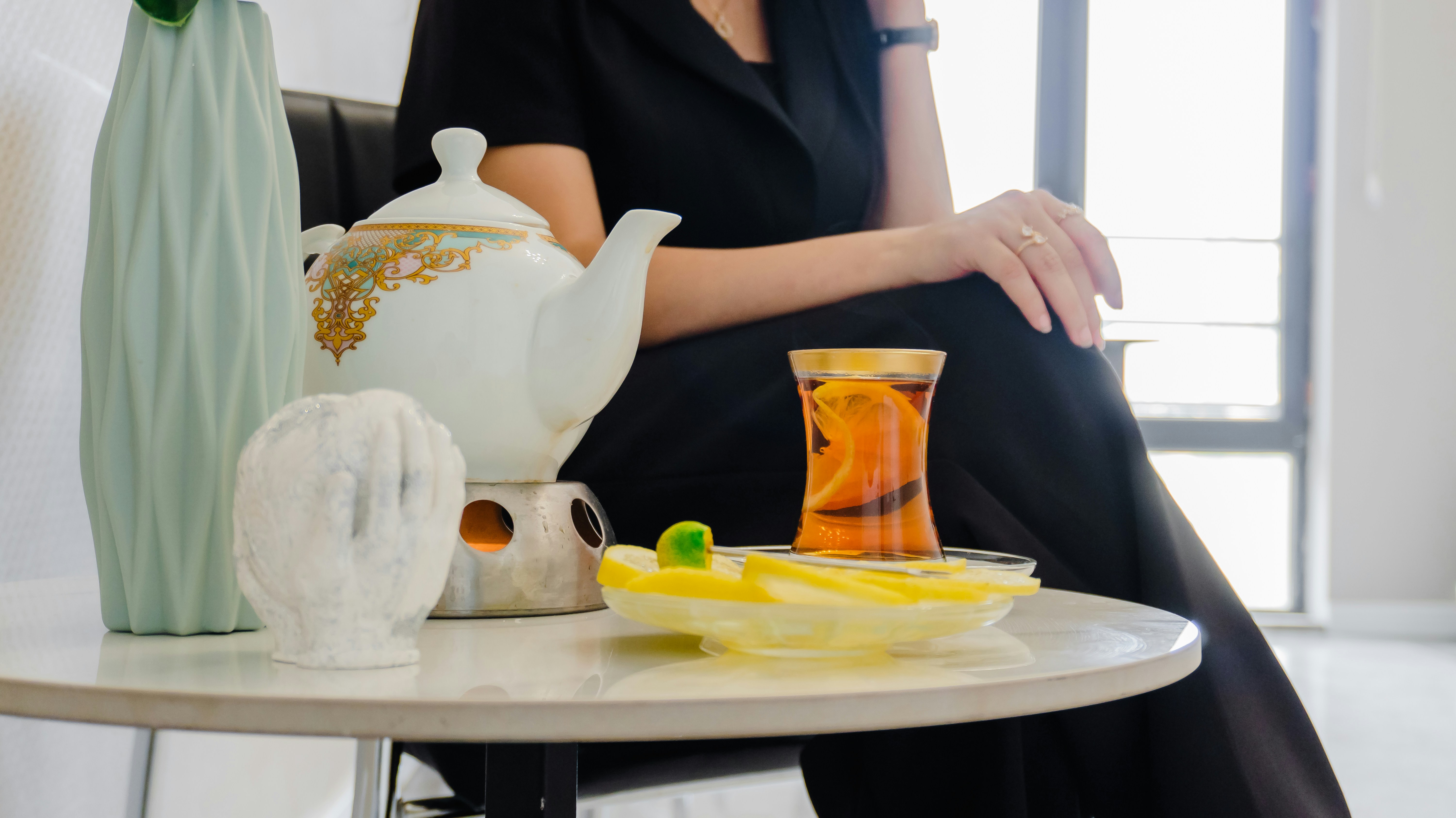 Elegant tea set accompanied by a refreshing drink and a platter of citrus fruits, set against a minimalist backdrop. The scene exudes a sense of calm and leisure.