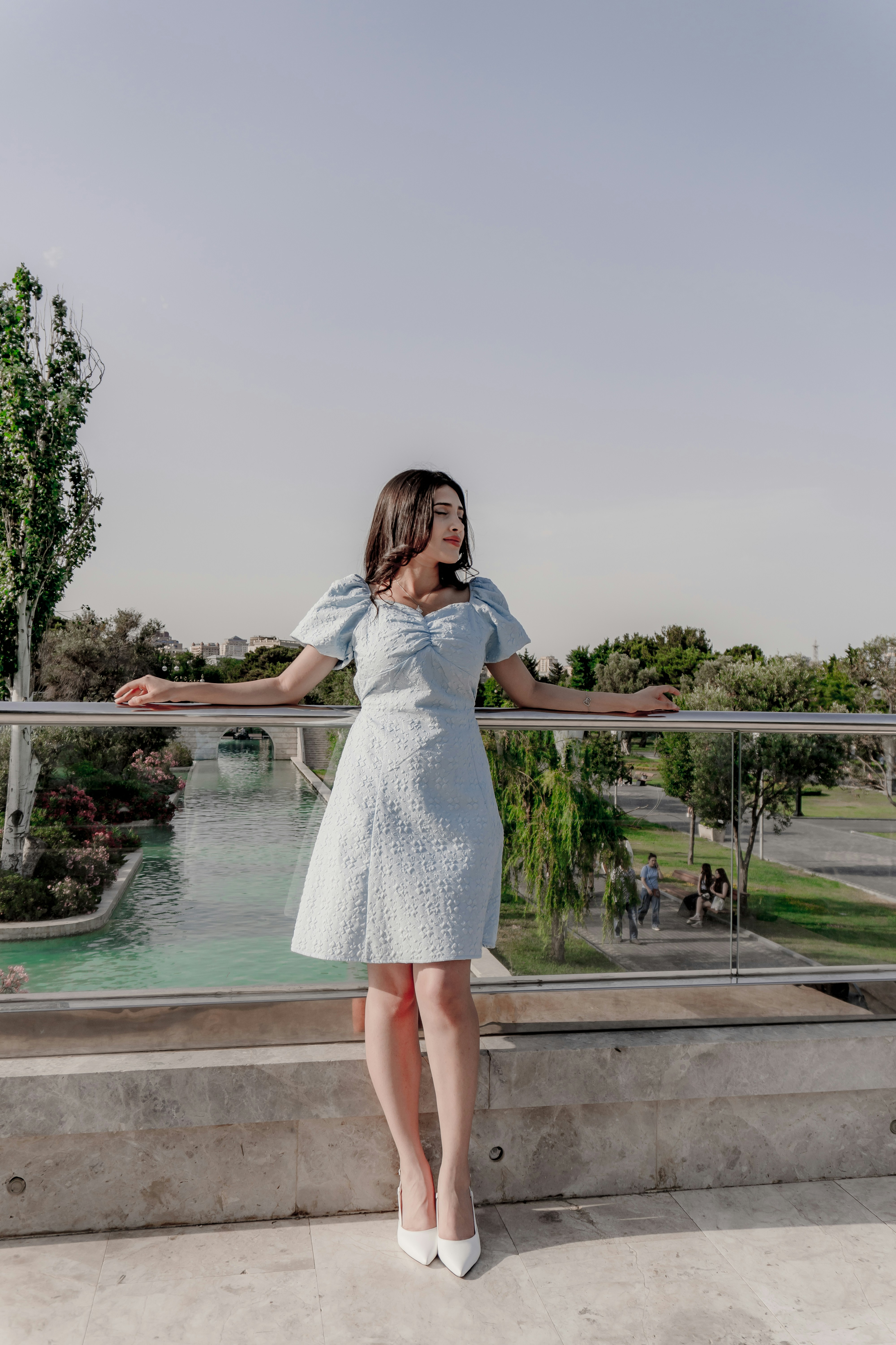 White Dress on a Balcony: Poised Portrait with City Park Backdrop