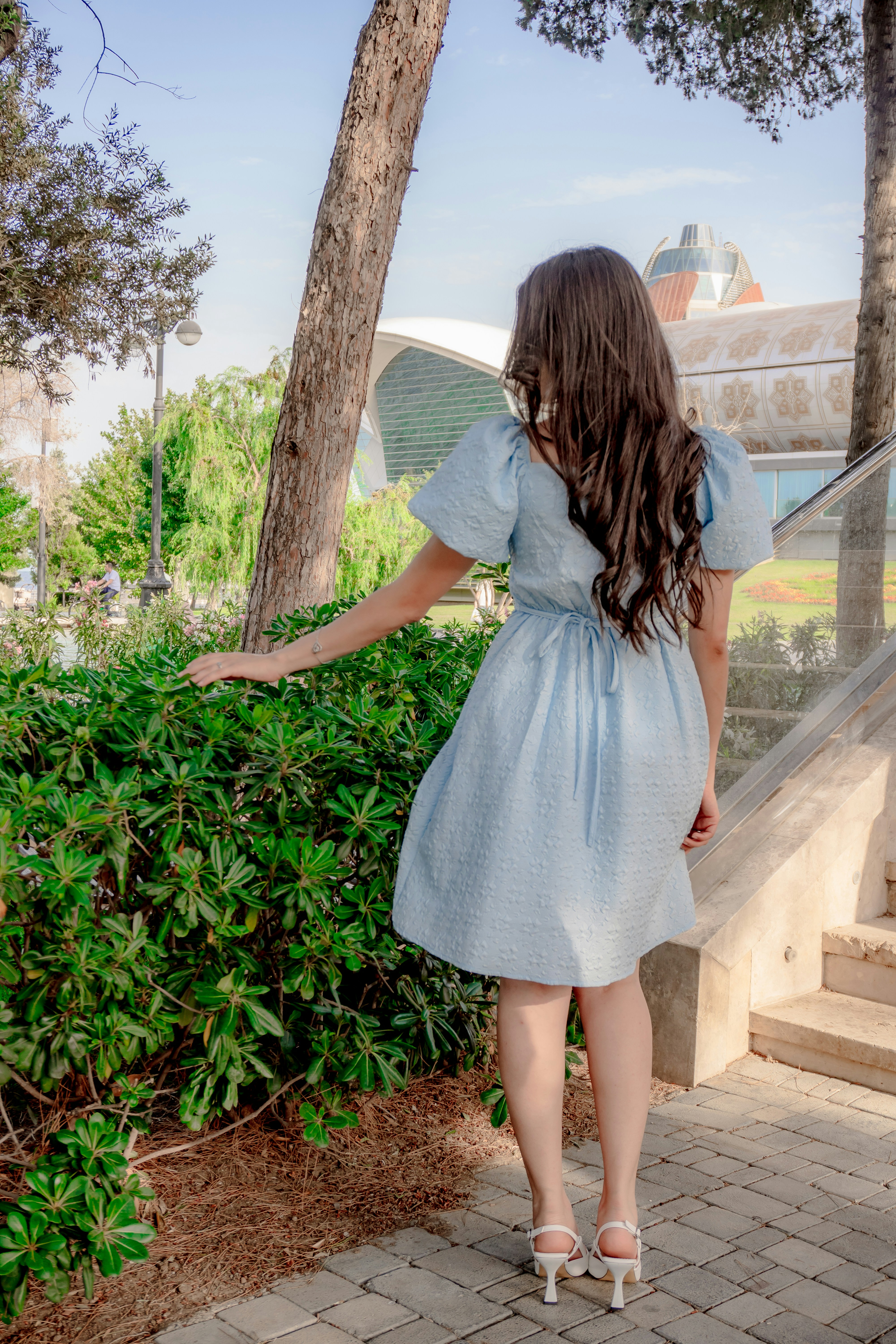 Powder-Blue Poise: A Back View Against a Modern Garden of Curves
